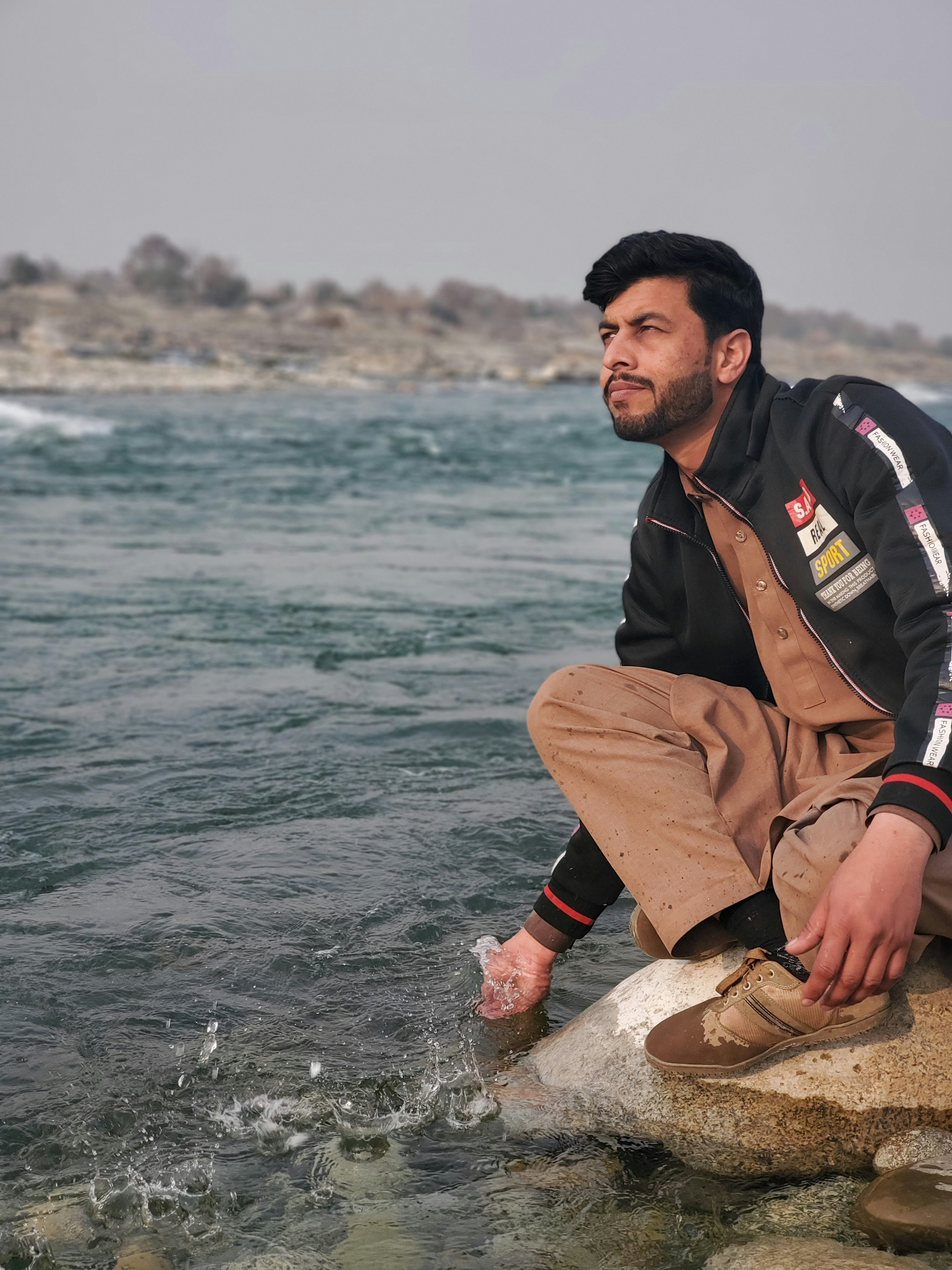 Man touching water by a flowing river