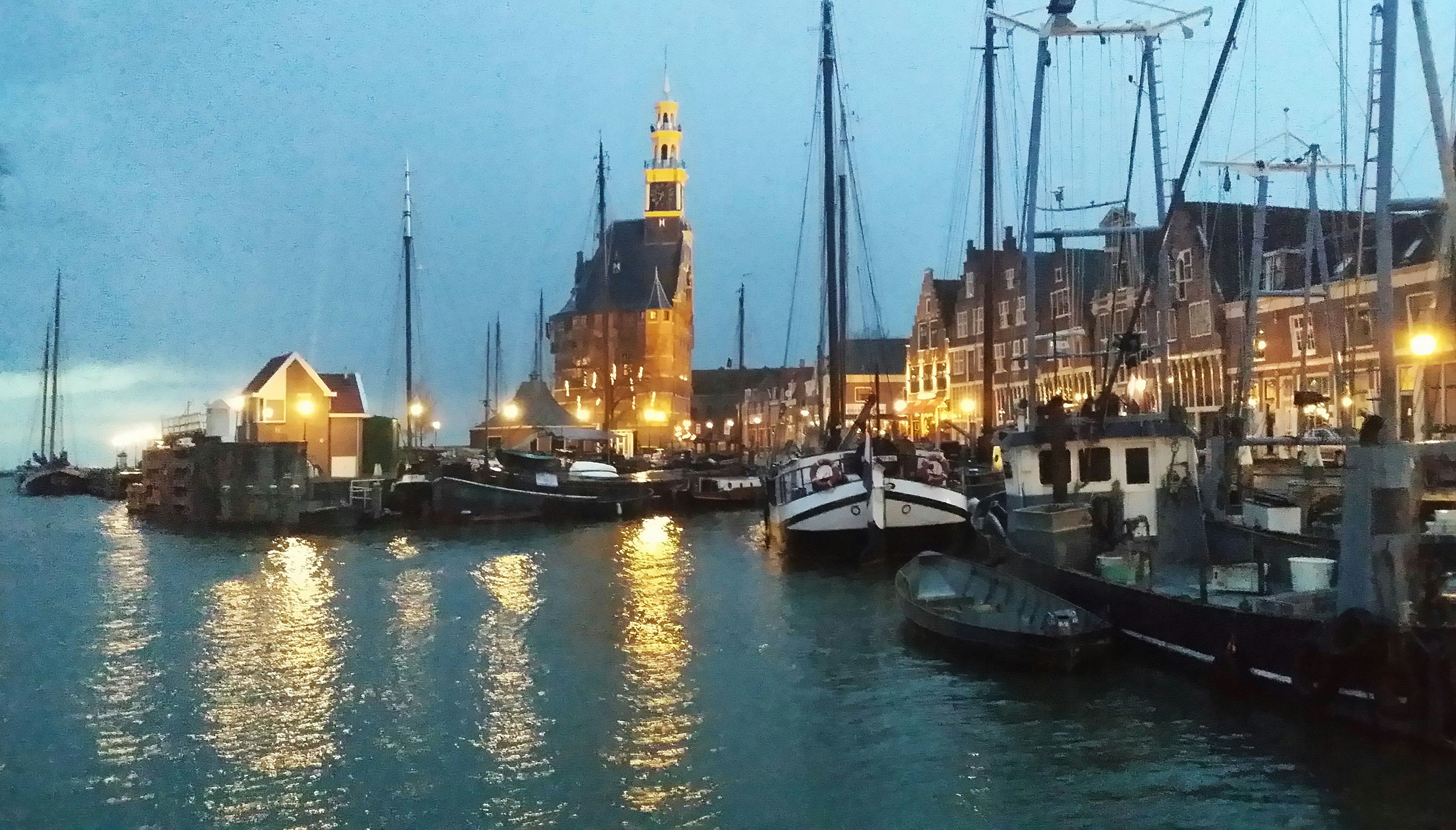 Boats docked in a harbor with historic buildings at dusk.