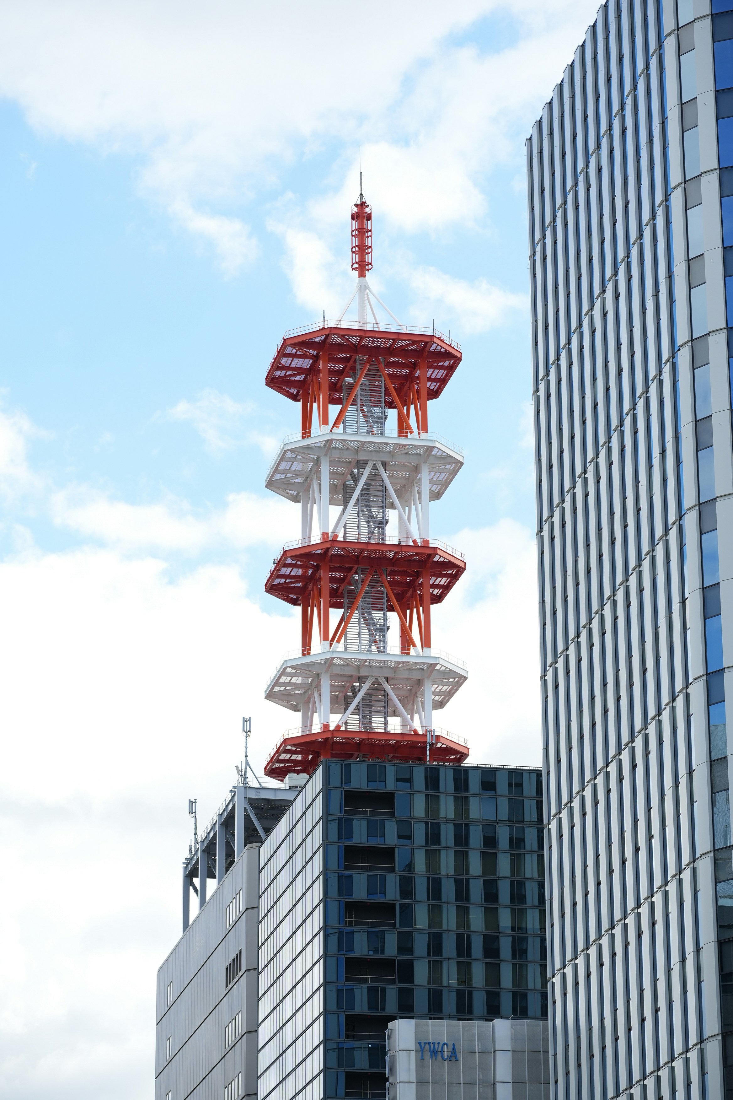 Red-and-White Telecommunication Tower Rises Between Modern skyscrapers