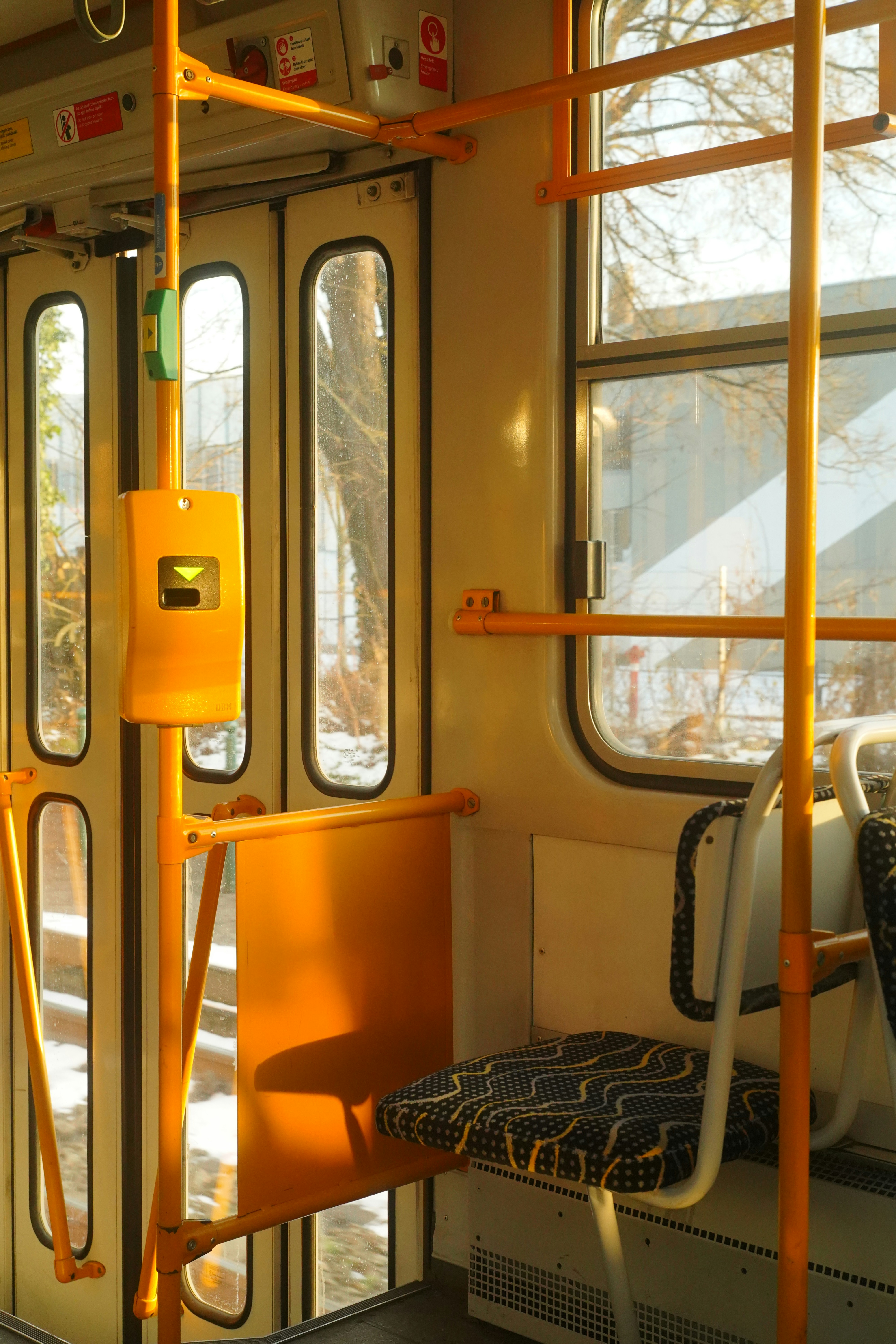 Orange rails and sunlight on a quiet bus interior