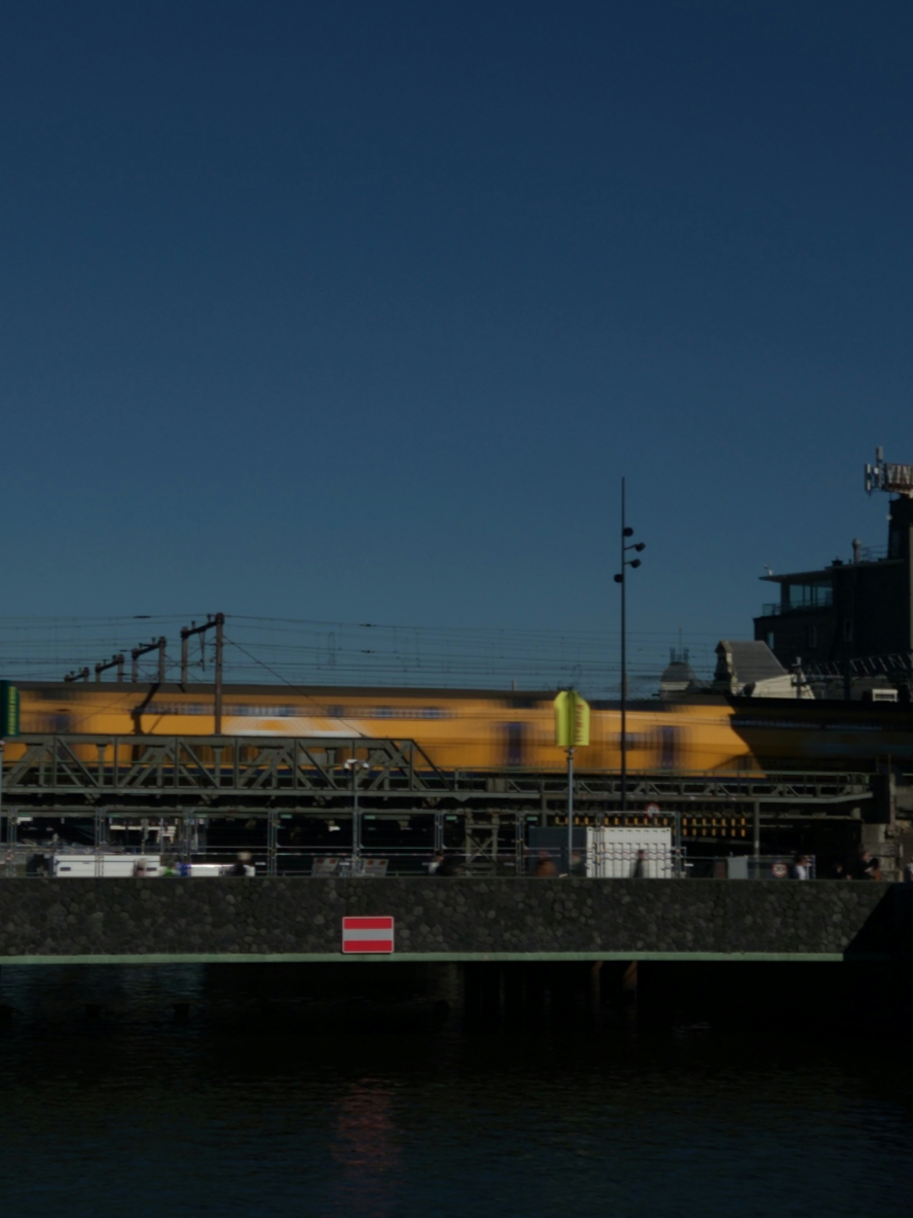 A yellow train moves quickly across a bridge.