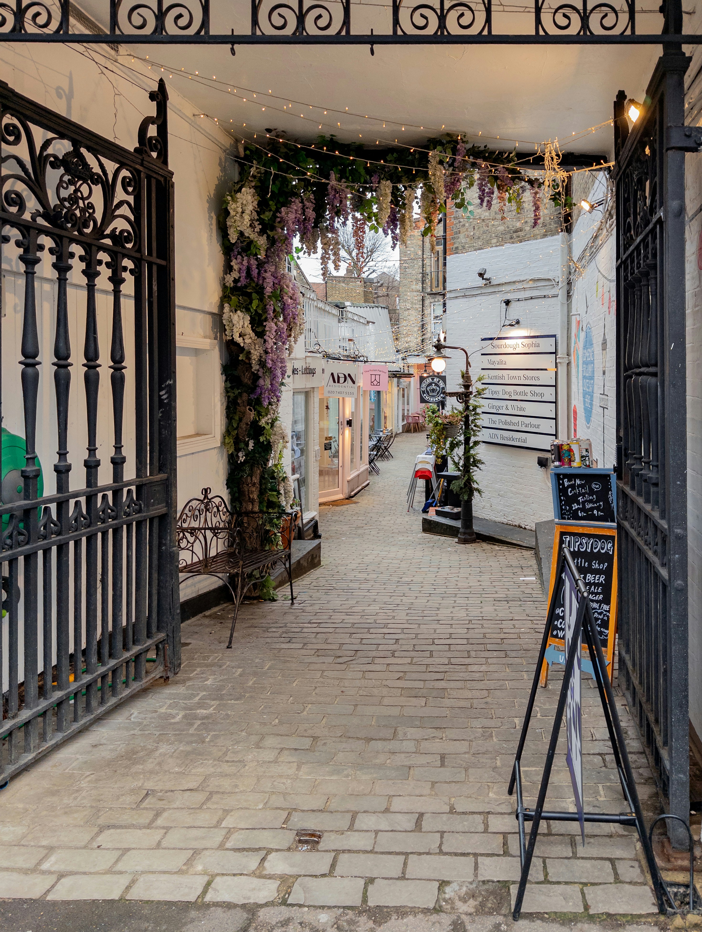 Cobbled Lane Under Floral Canopy