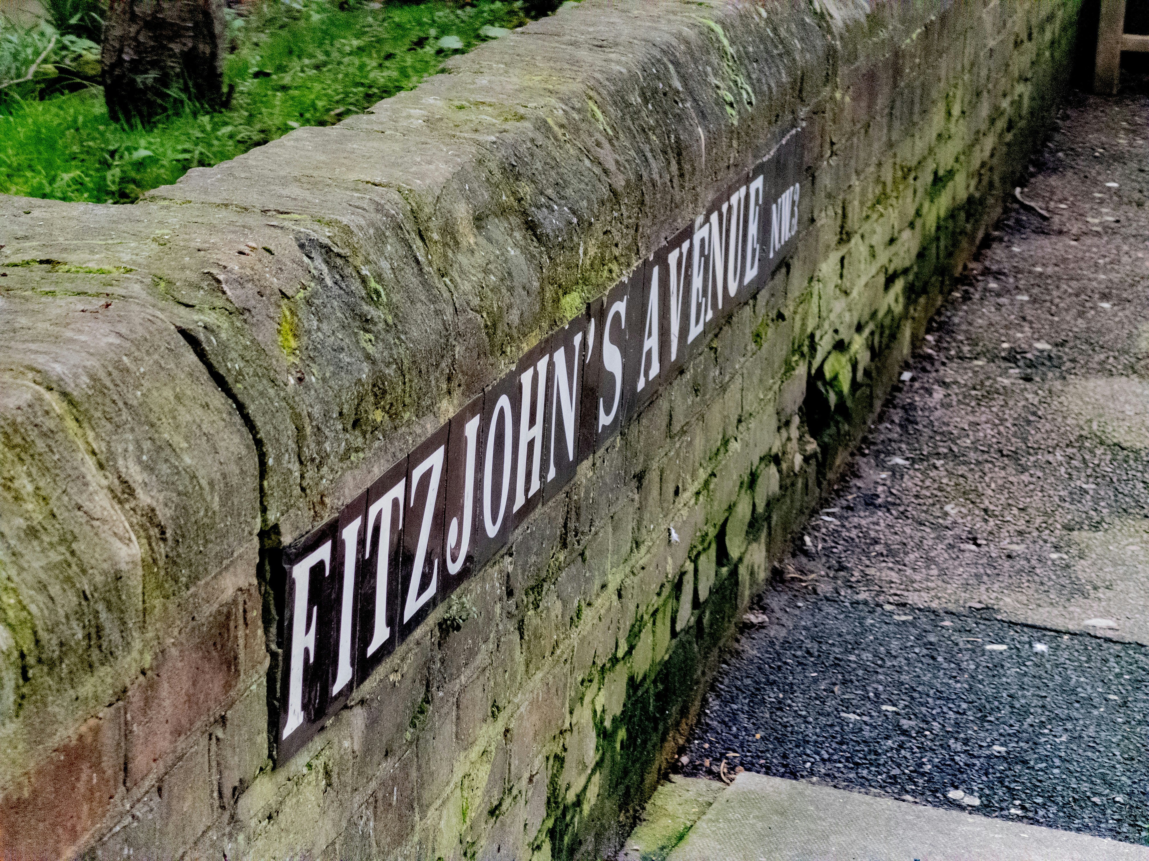 Moss-Capped Street Sign: Fitzjohn’s Avenue Along a Weathered Retaining Wall