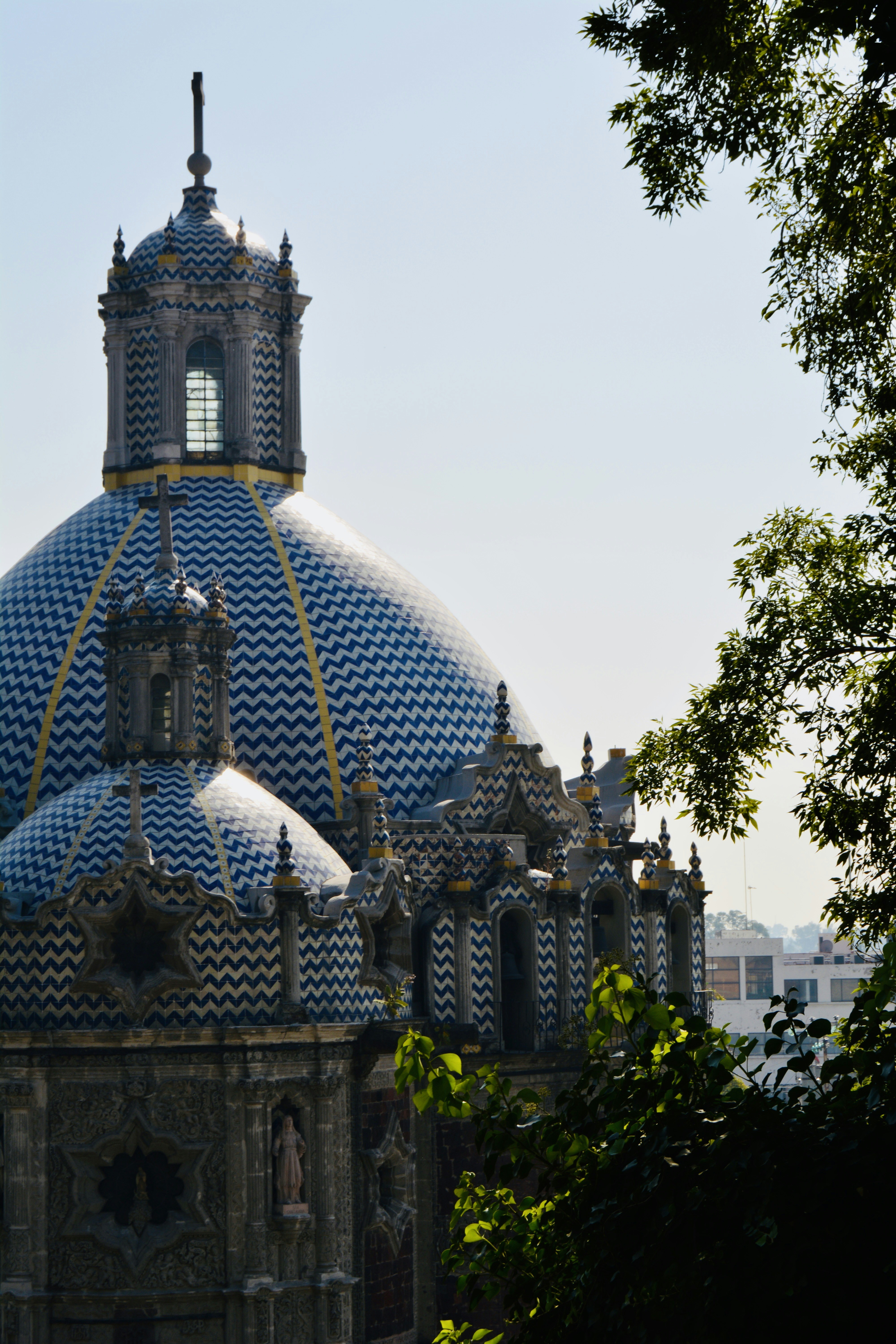 Blue-diamond dome rising above intricate masonry in a sunlit plaza