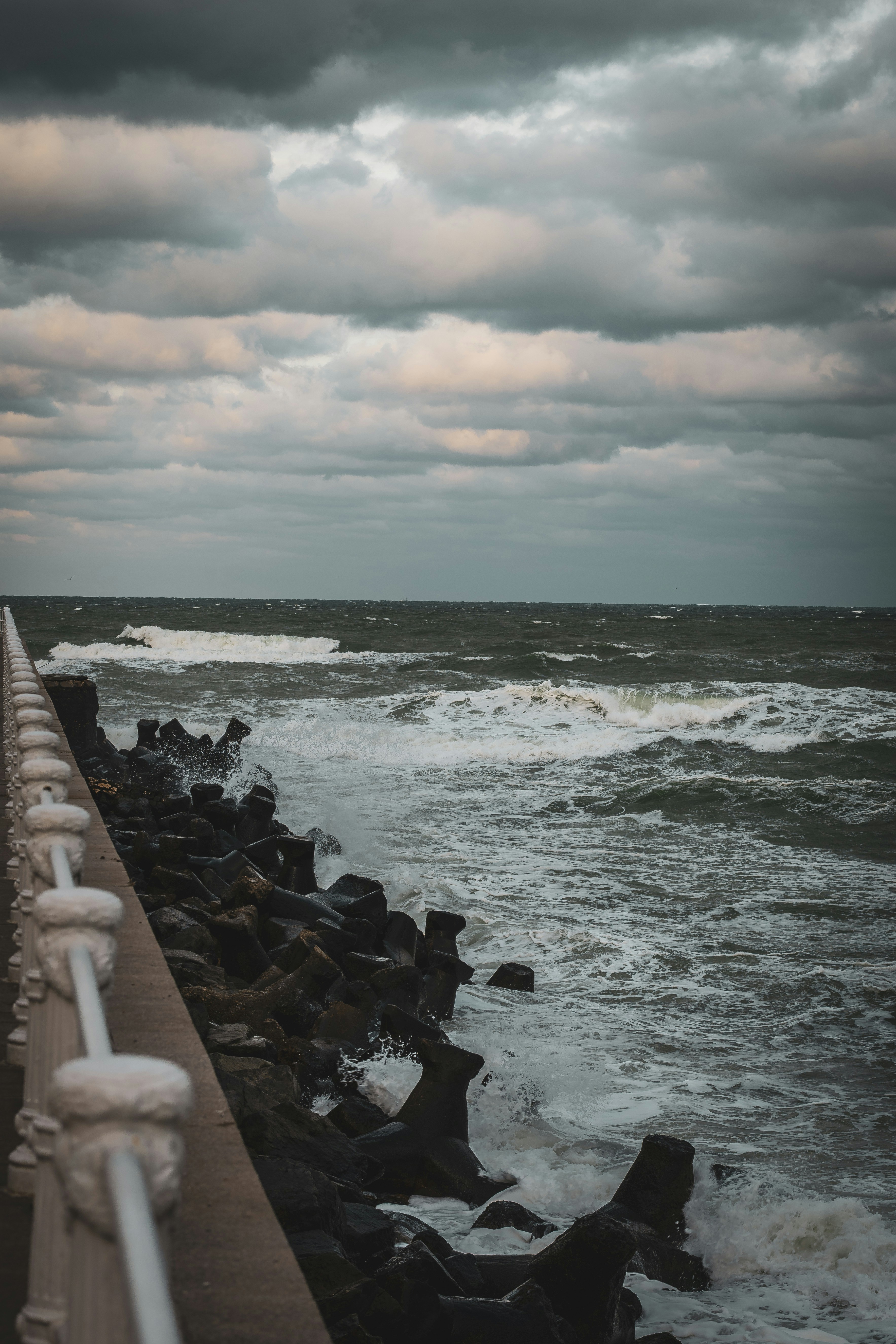 Stormy Promenade: Waves Clash Along a Breakwater