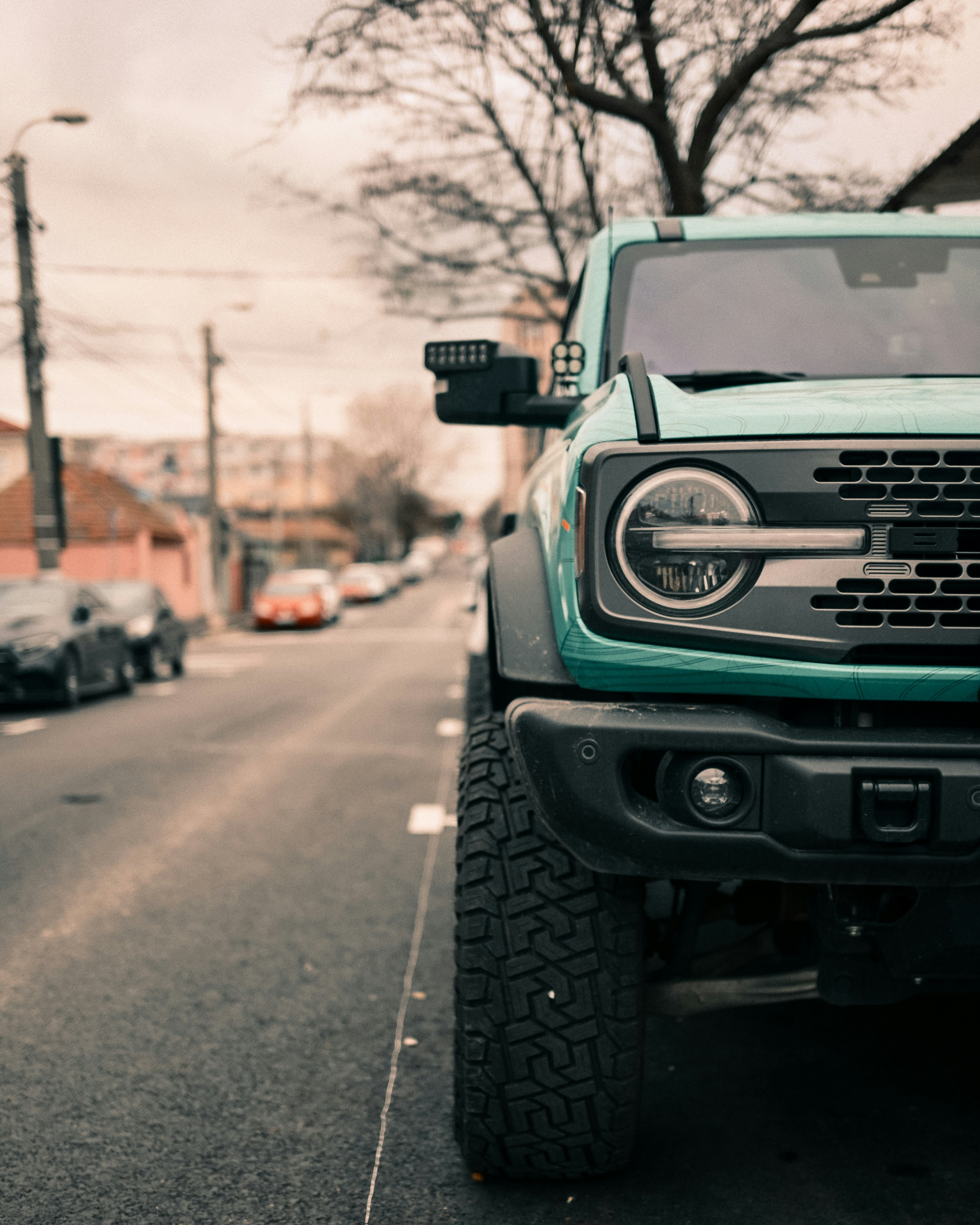 Front-Quarter Power: A teal off-roader commanding a sunliturban street