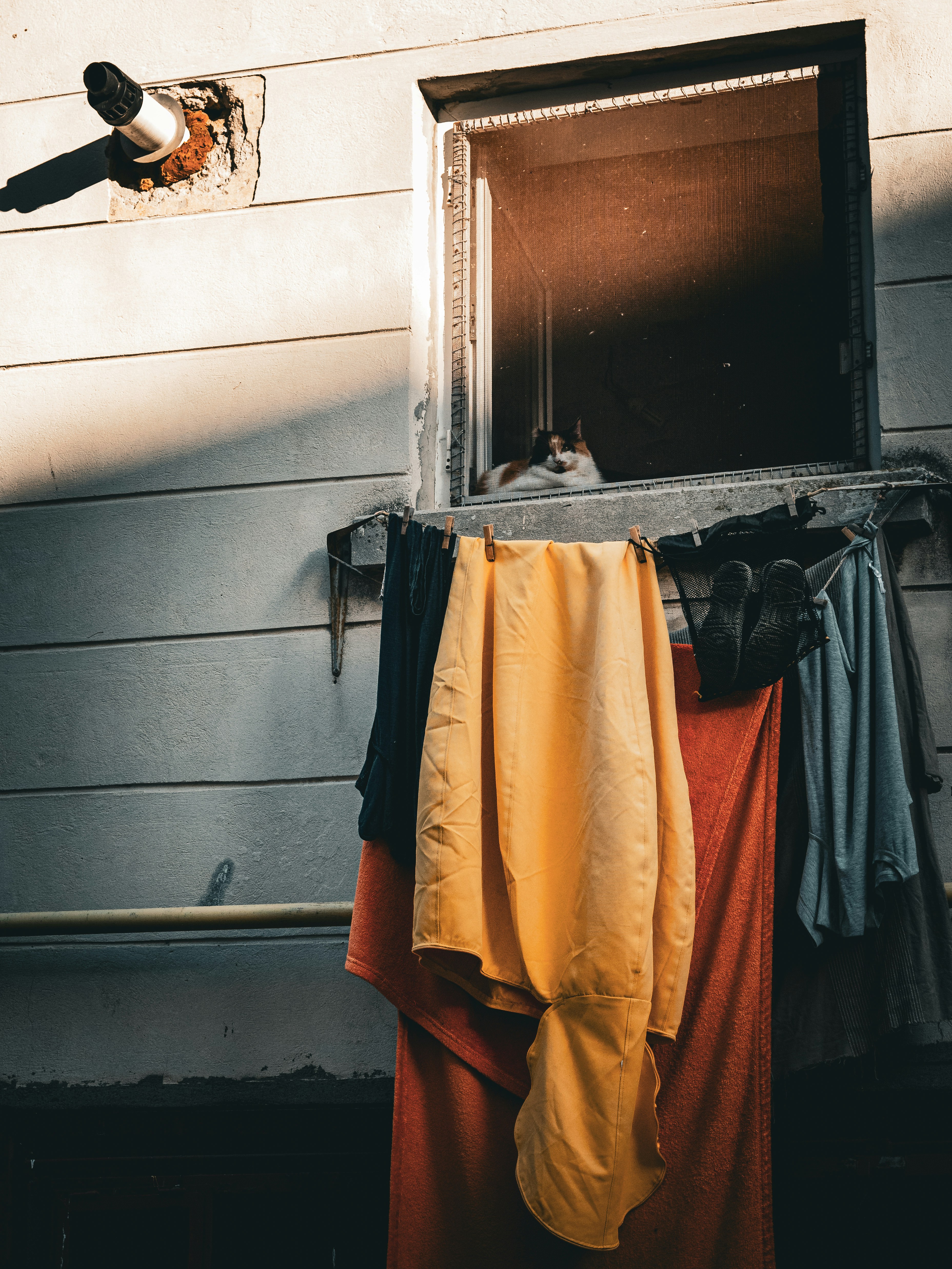 Drying laundry under a sunlit window on a weathered facade