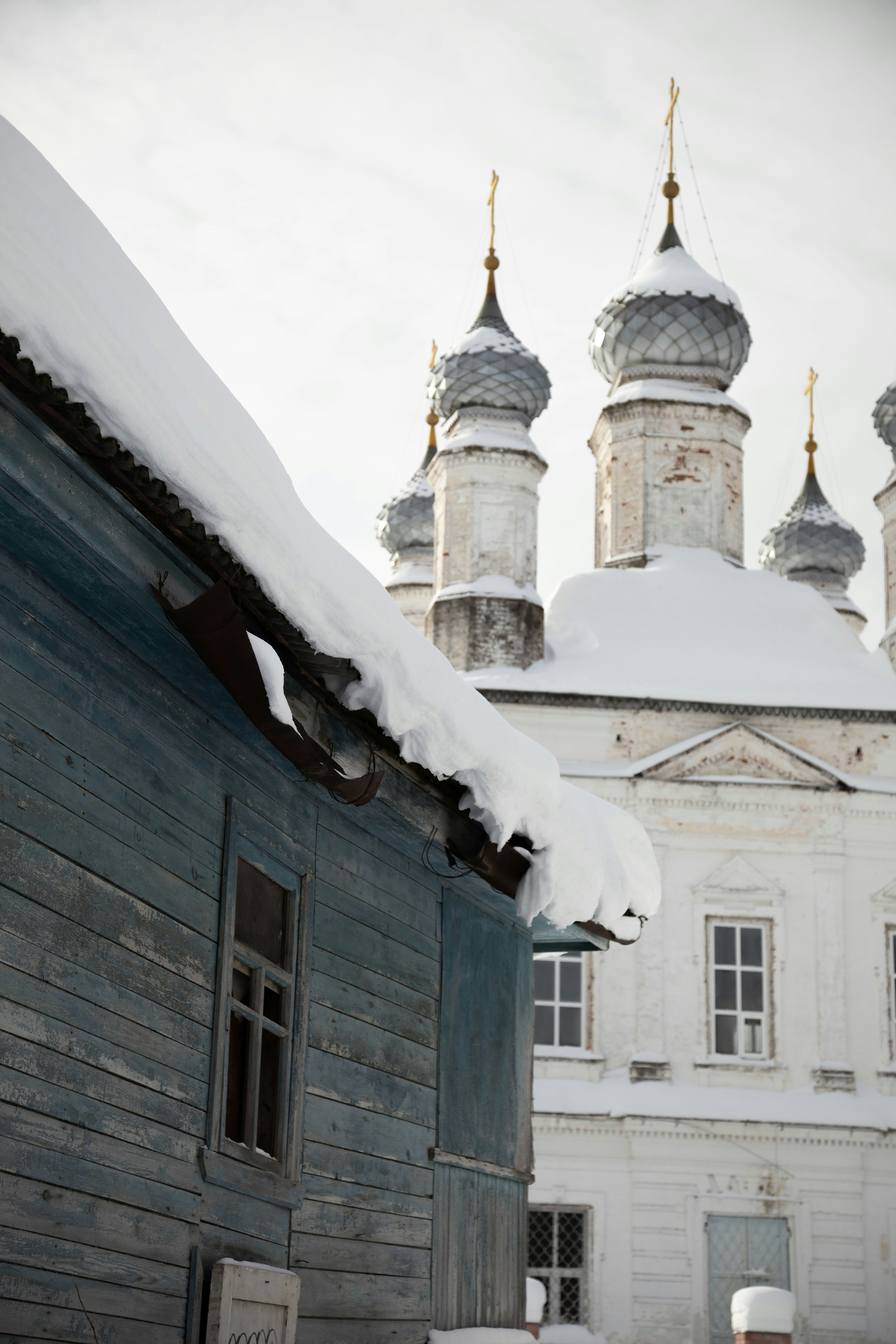 Snowbound Cathedral Silhouette Behind A Weathered Blue House