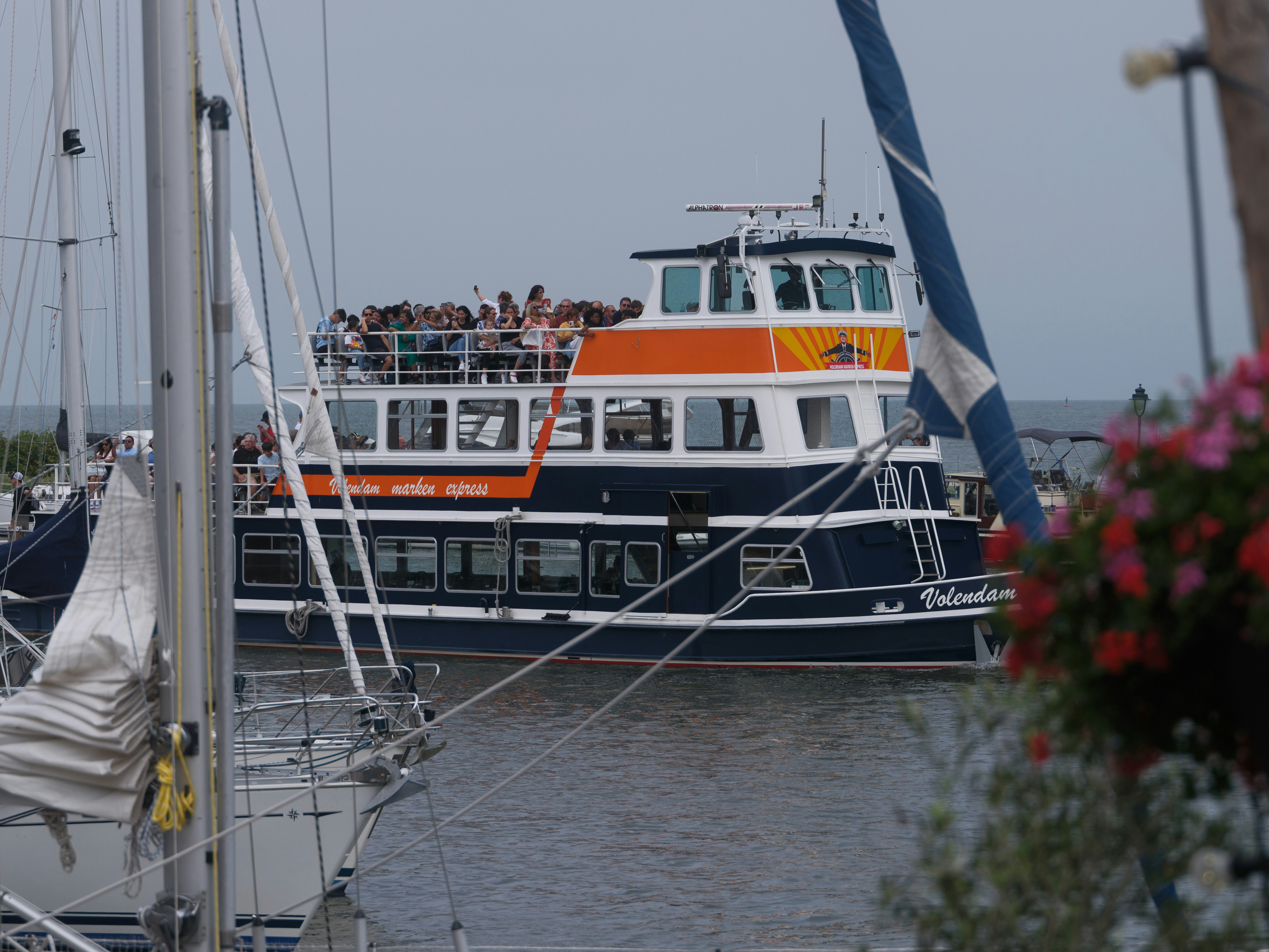 Crowded Harbor Tour: Passengers On Deck Amid Sails and Masts