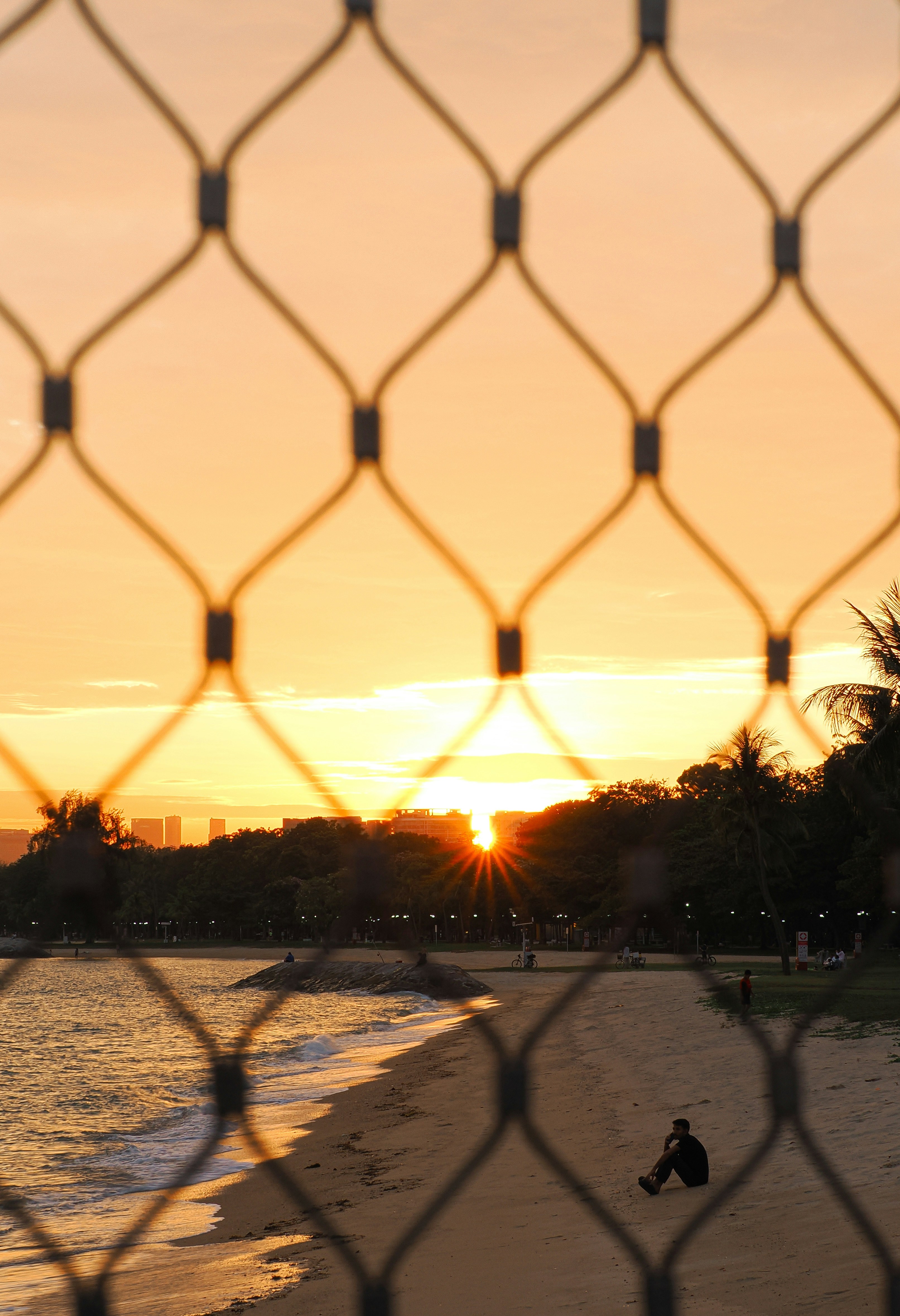 Sunset Beyond the Fence: Beach, Shadow, and Chain-link Geometry