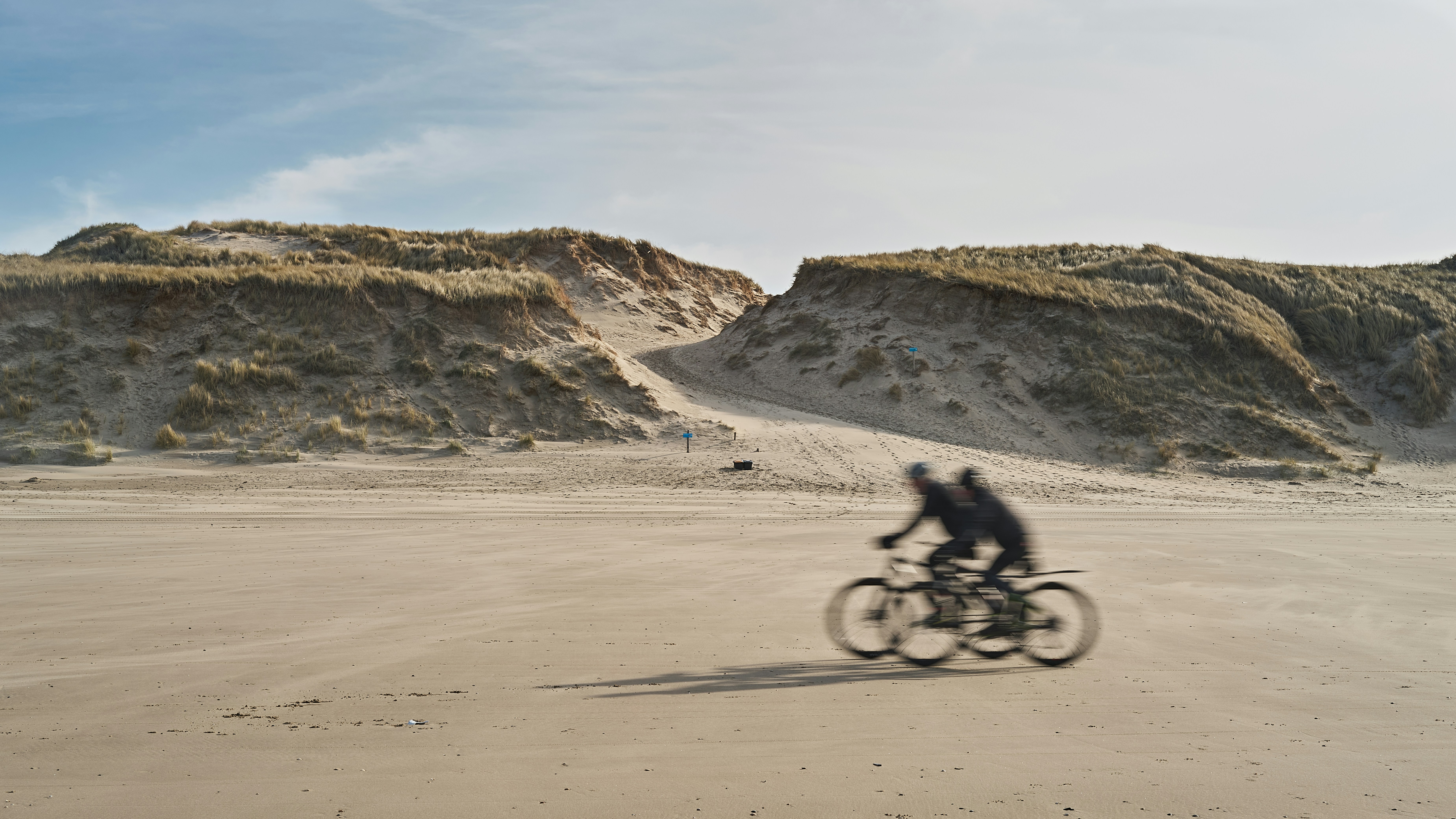 Blurry Riders on a Dune-Spun Coast