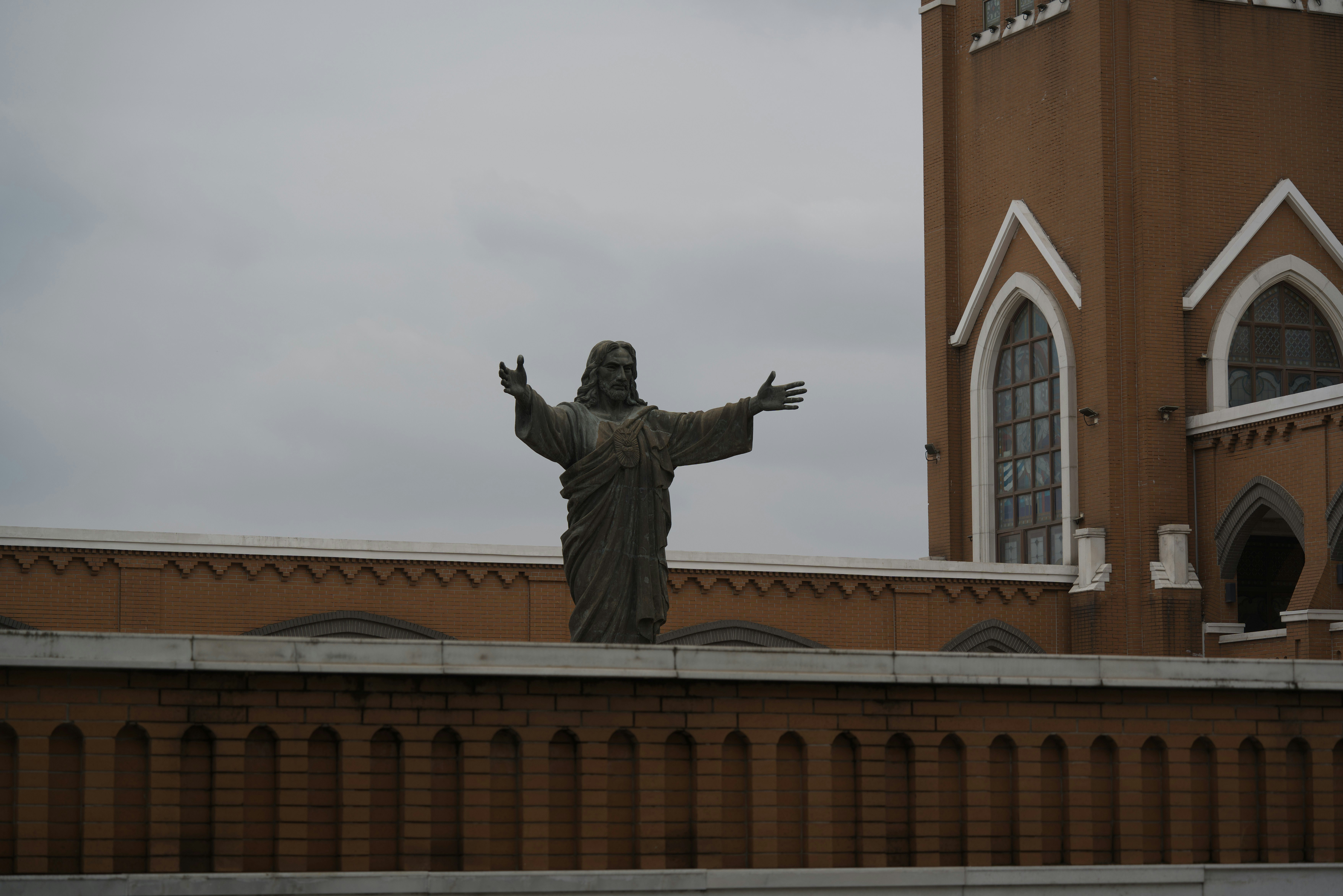 Arms Wide on the Aged Roof: A Statue Oversees the City