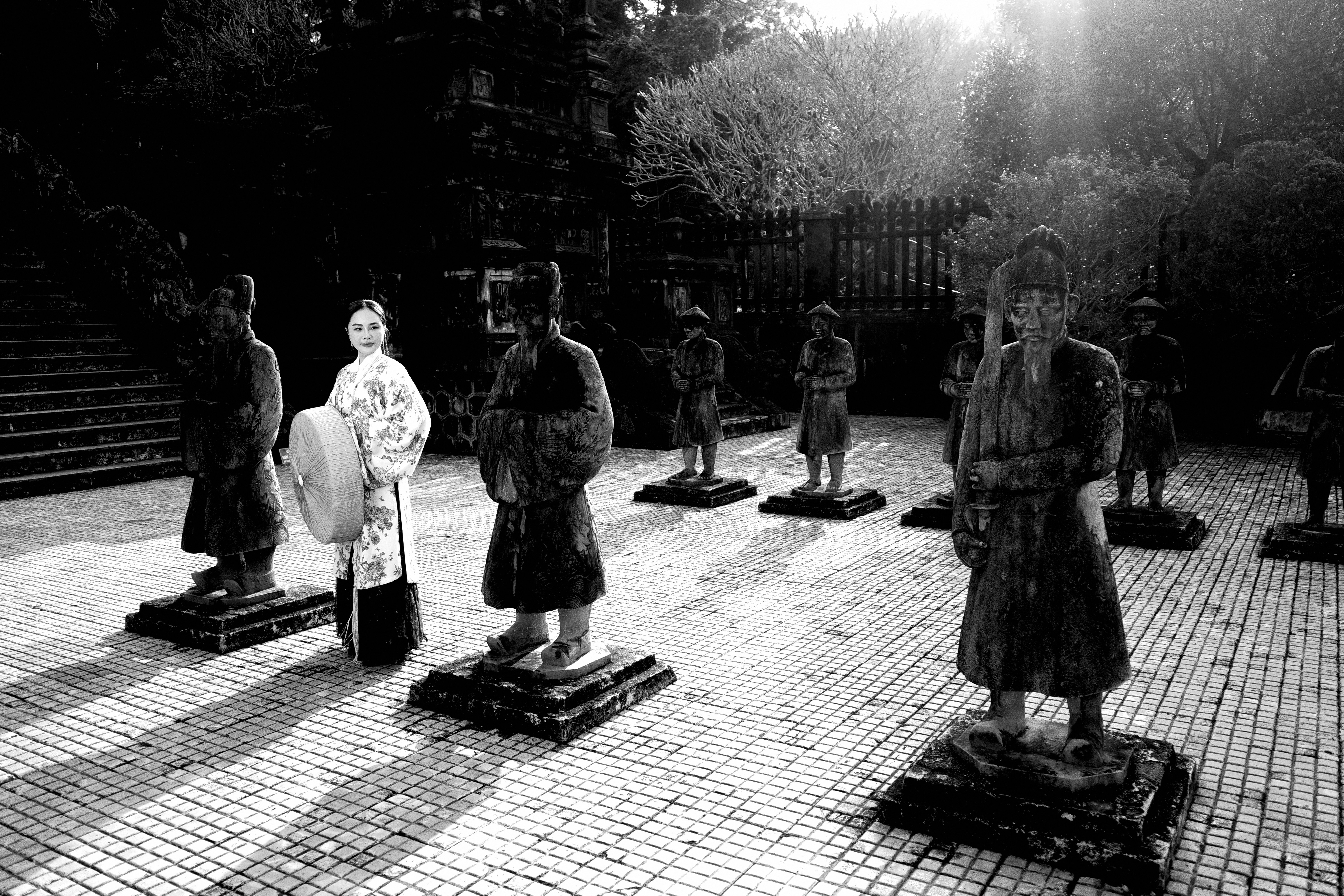 Silent Observers: Eight Statues and a Subtle Figure in a Monochrome Courtyard