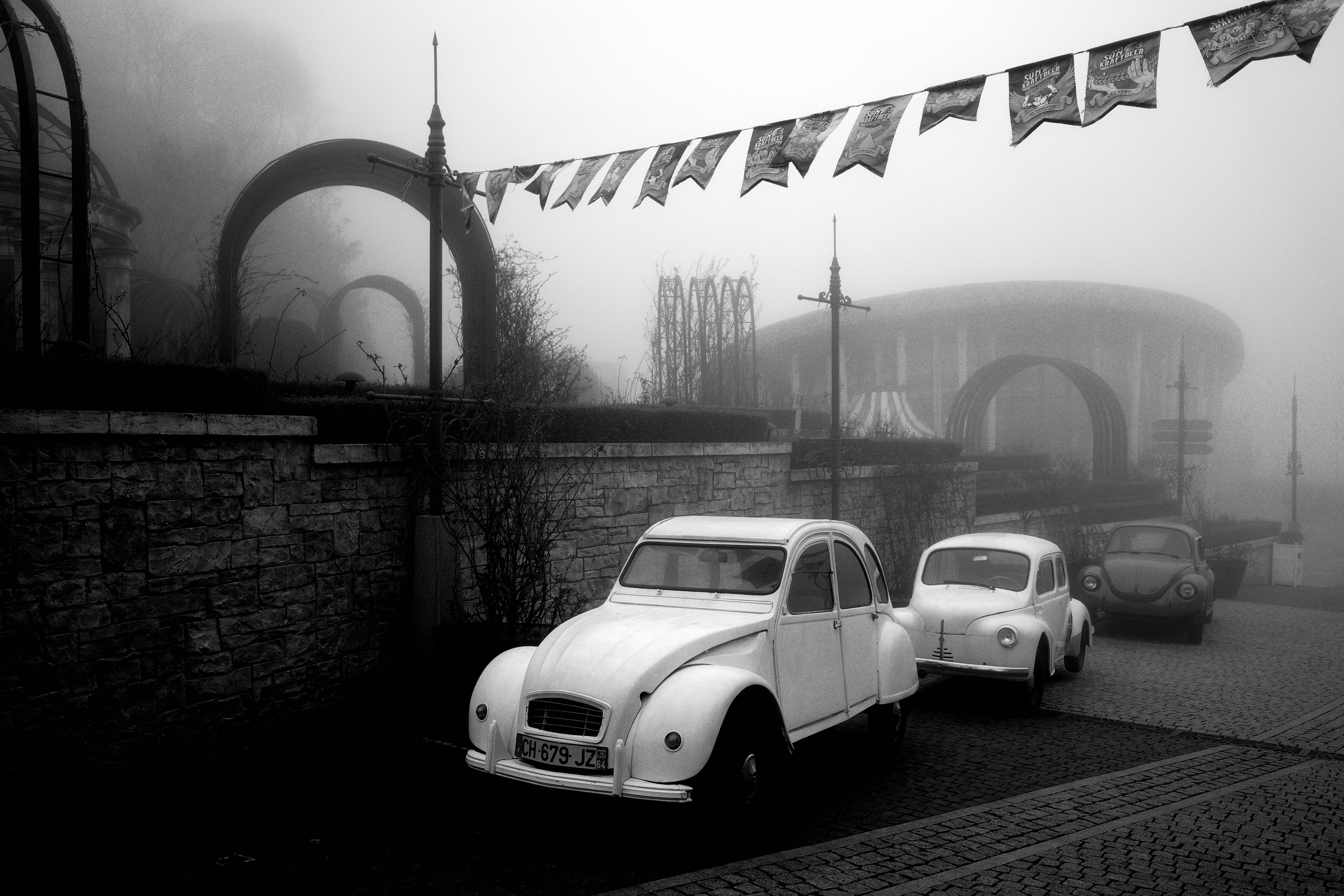 Vintage street in mist: cars, arches and pennant banners fading into fog