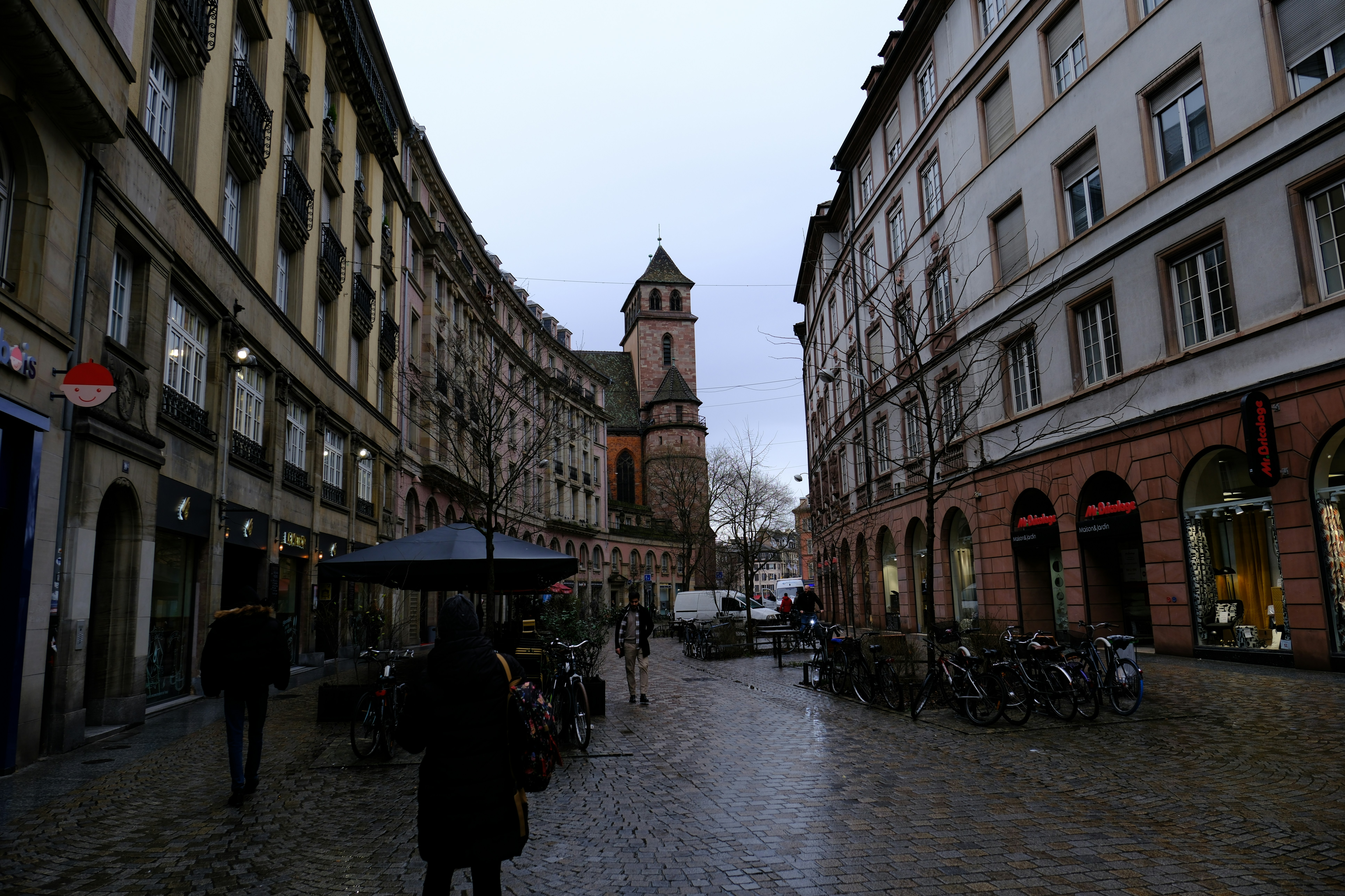 Cobblestone Street with a Clock Tower Aiming Through a Narrow European Alley