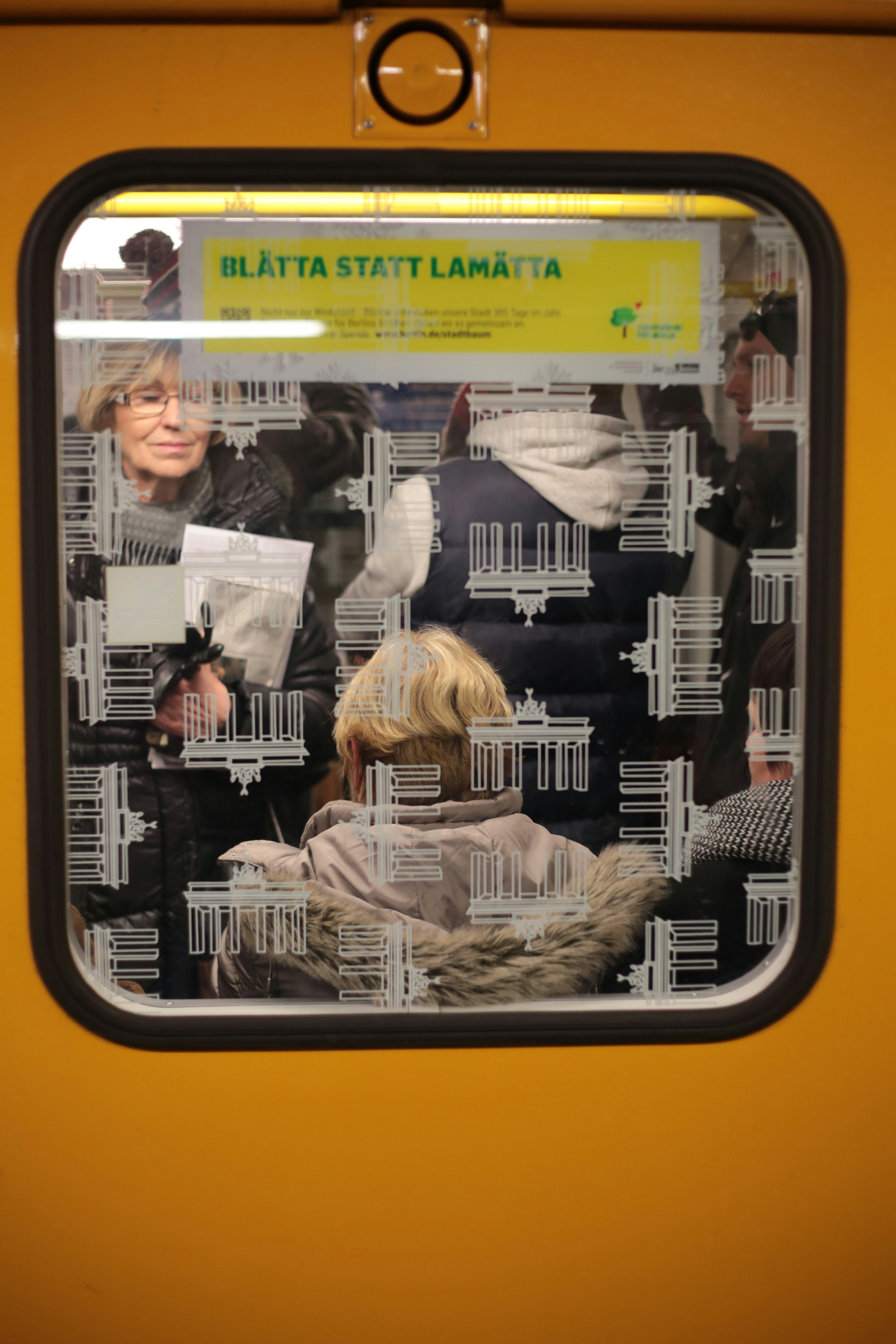 Crowded Window: People Framed Behind Urban Glass on a Yellow Transit Door