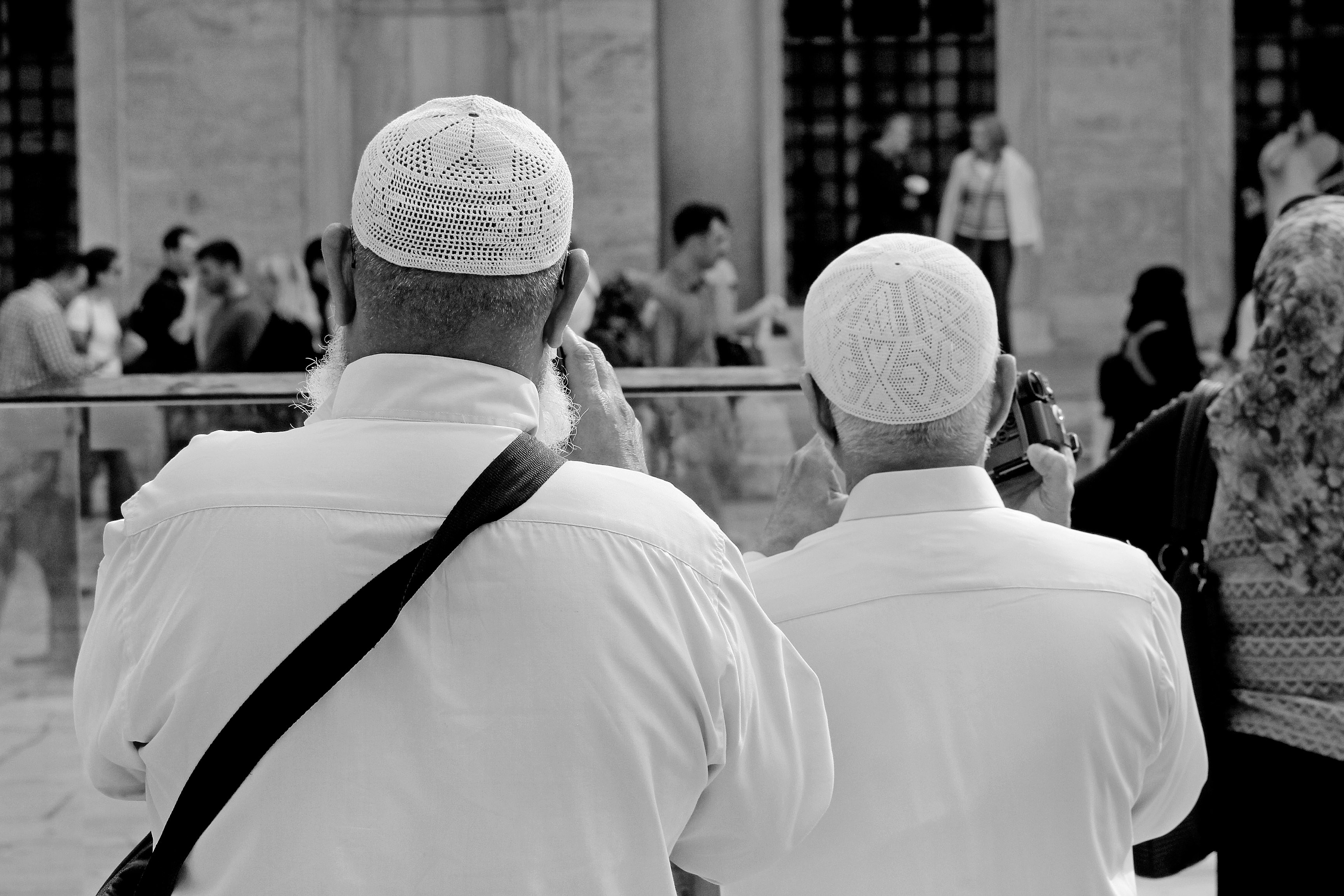 Backview of Two Clerics in White Attire at a Public Gathering