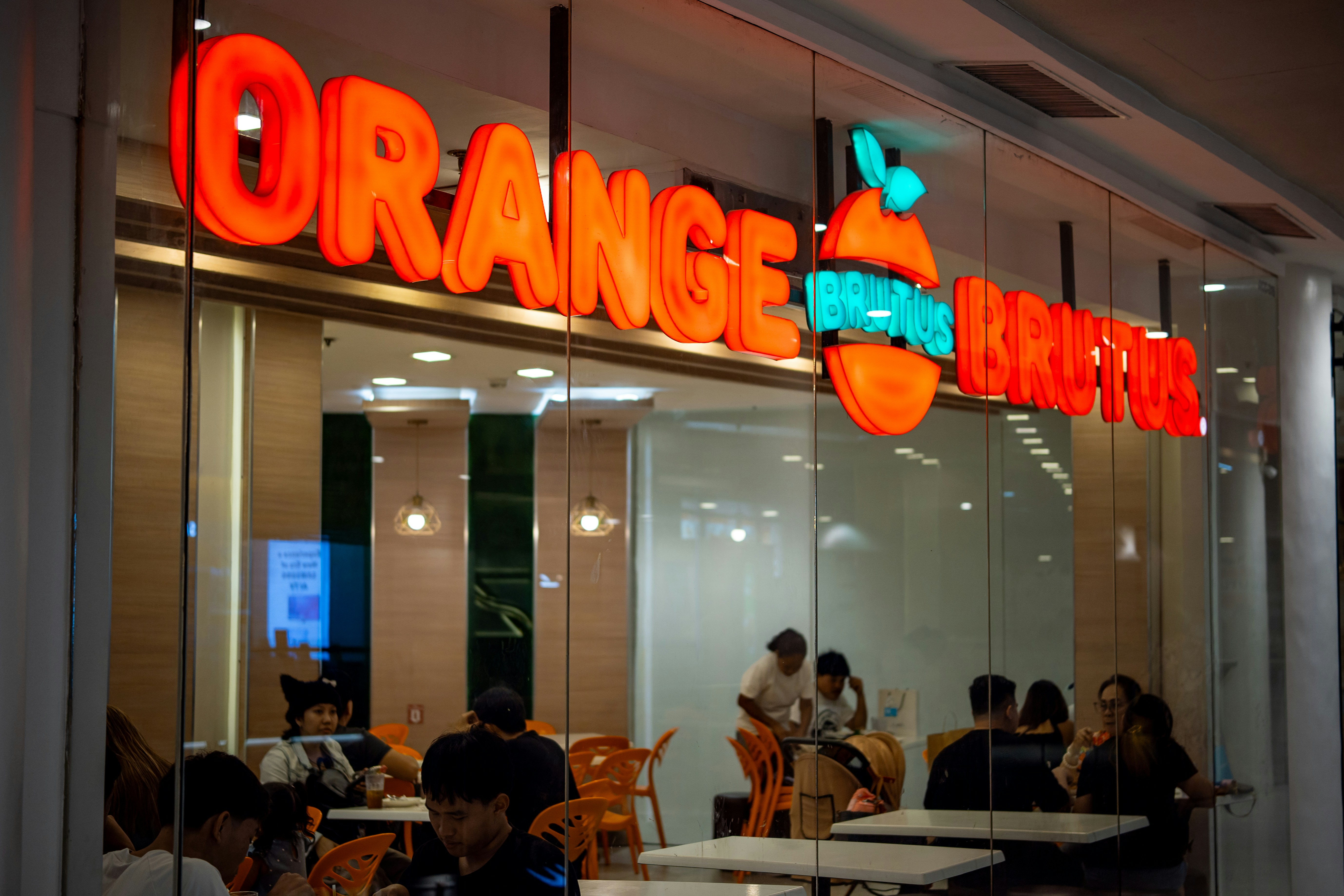 Neon Orange: A Glass-Front Café Bathed in Warm Night Glow