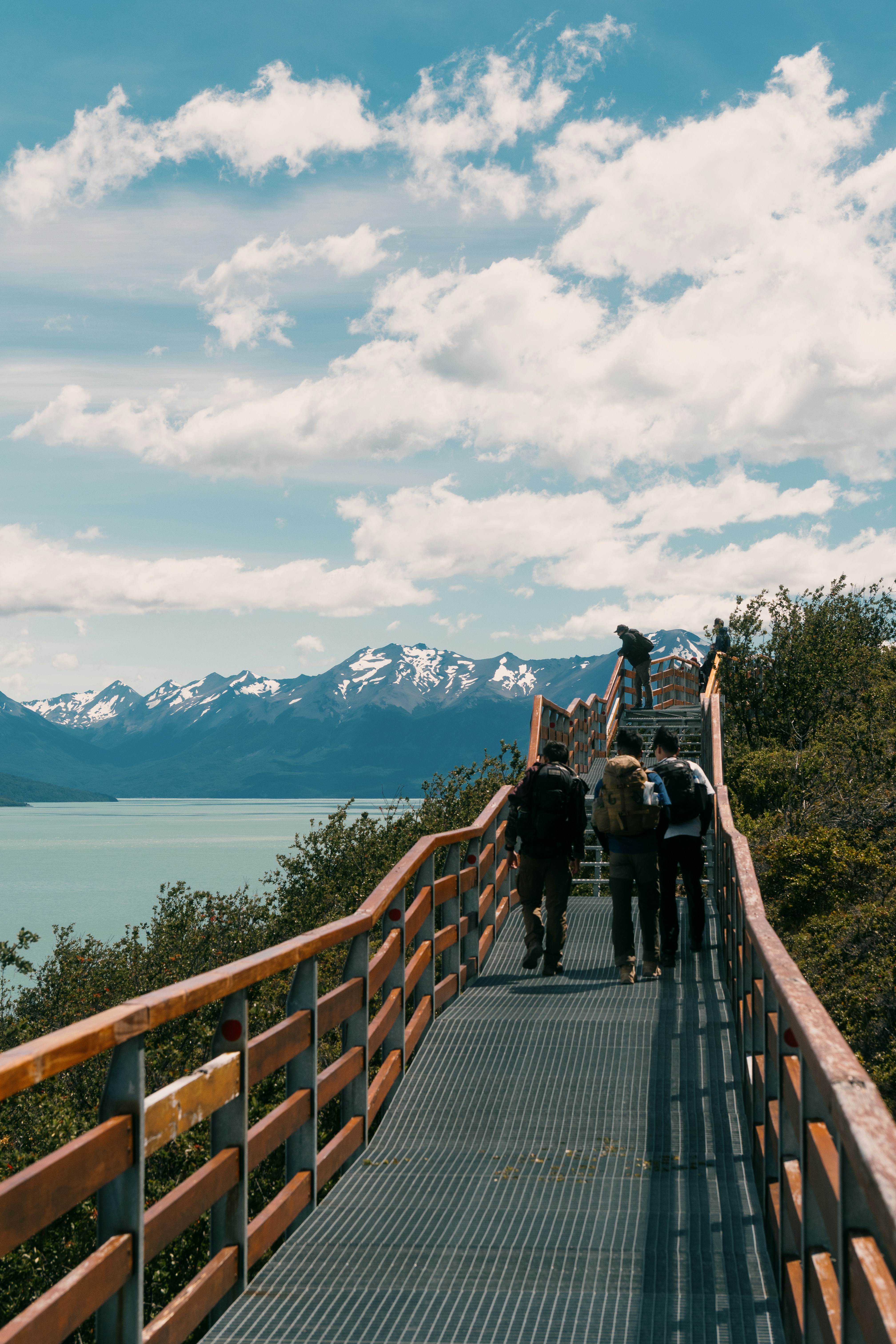 People walking on a wooden walkway towards mountains