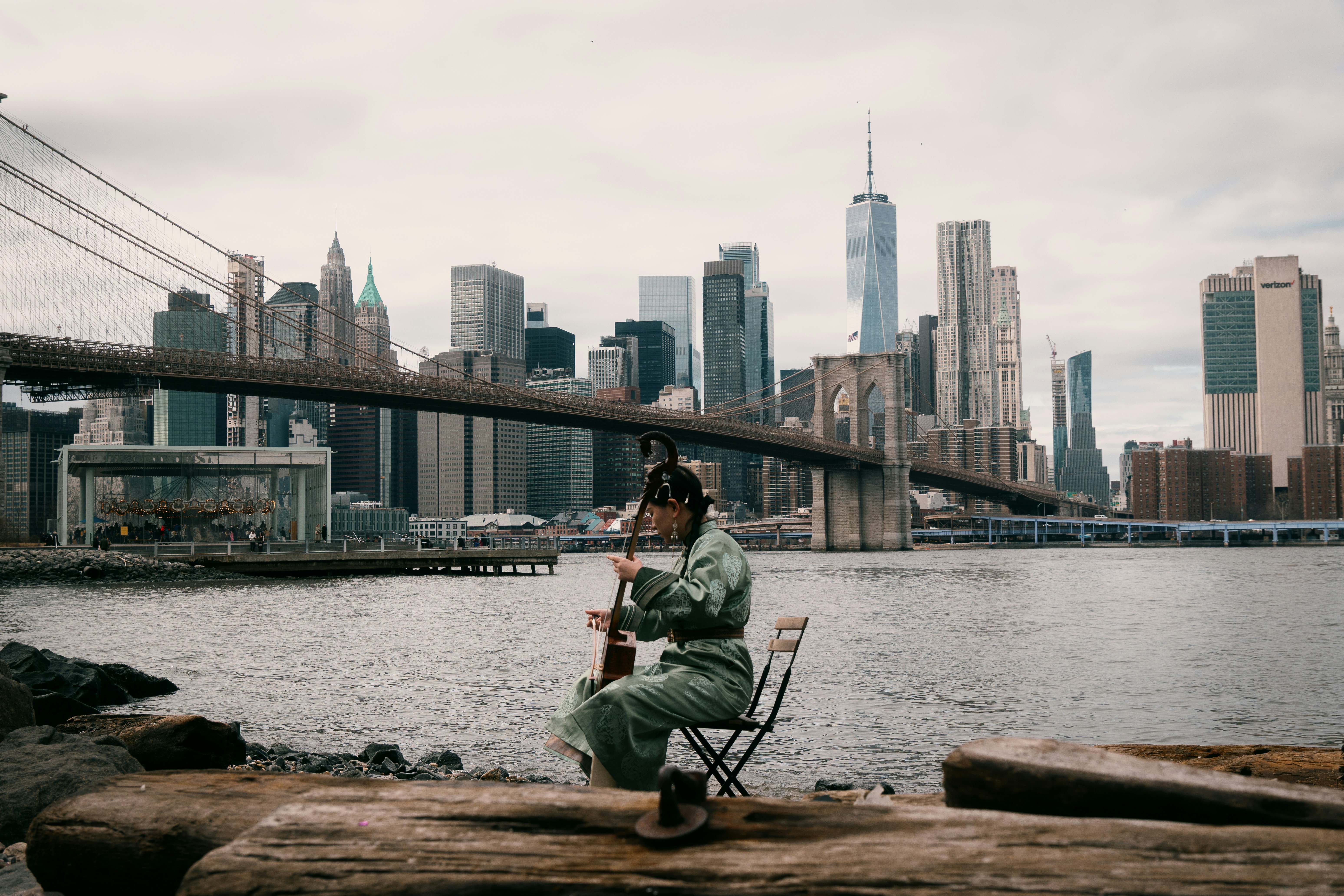 Brooklyn Bridge Serenade: a guitarist by the river with Manhattan skyline