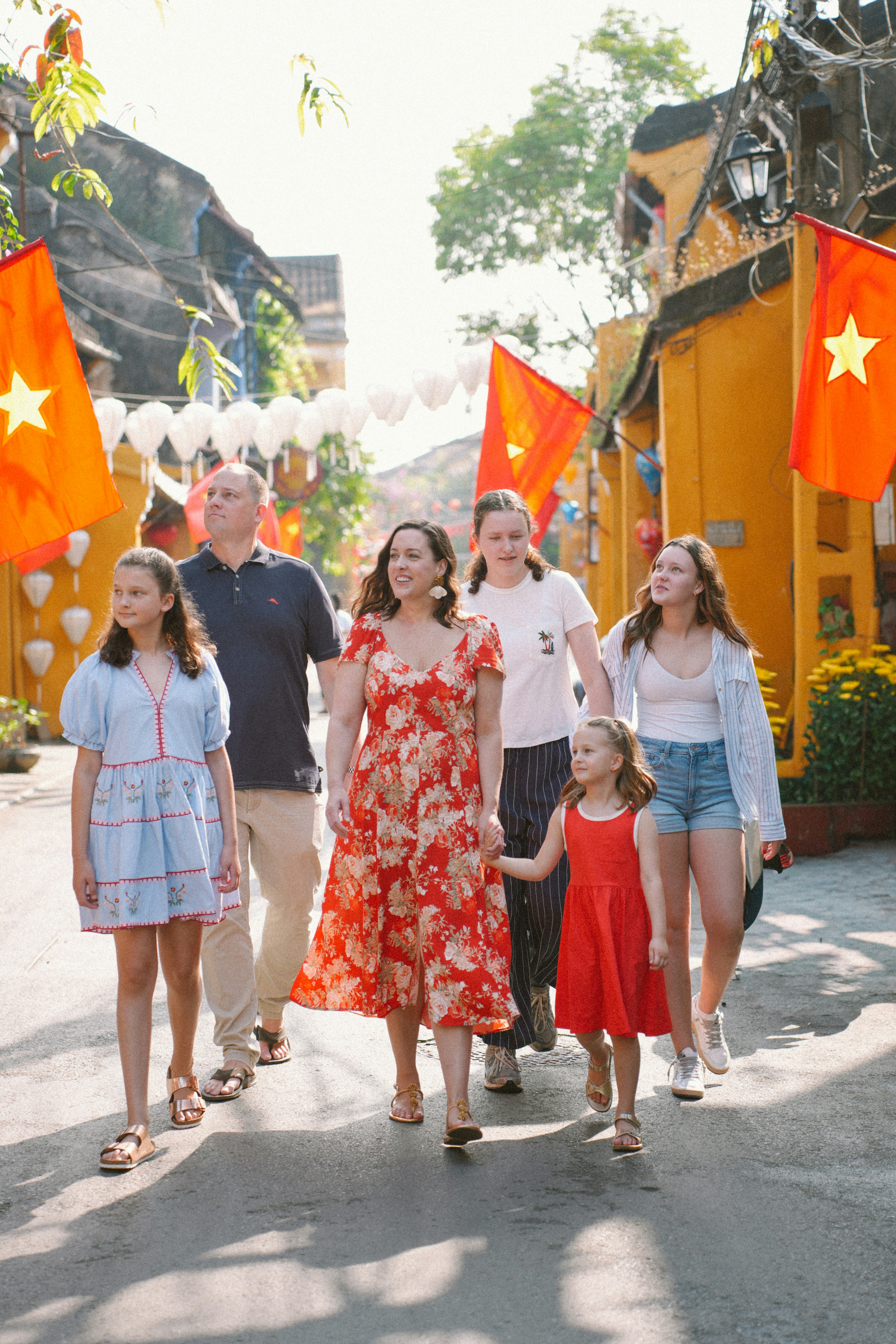 Family Parade Under Red Flags in a Sunlit Street