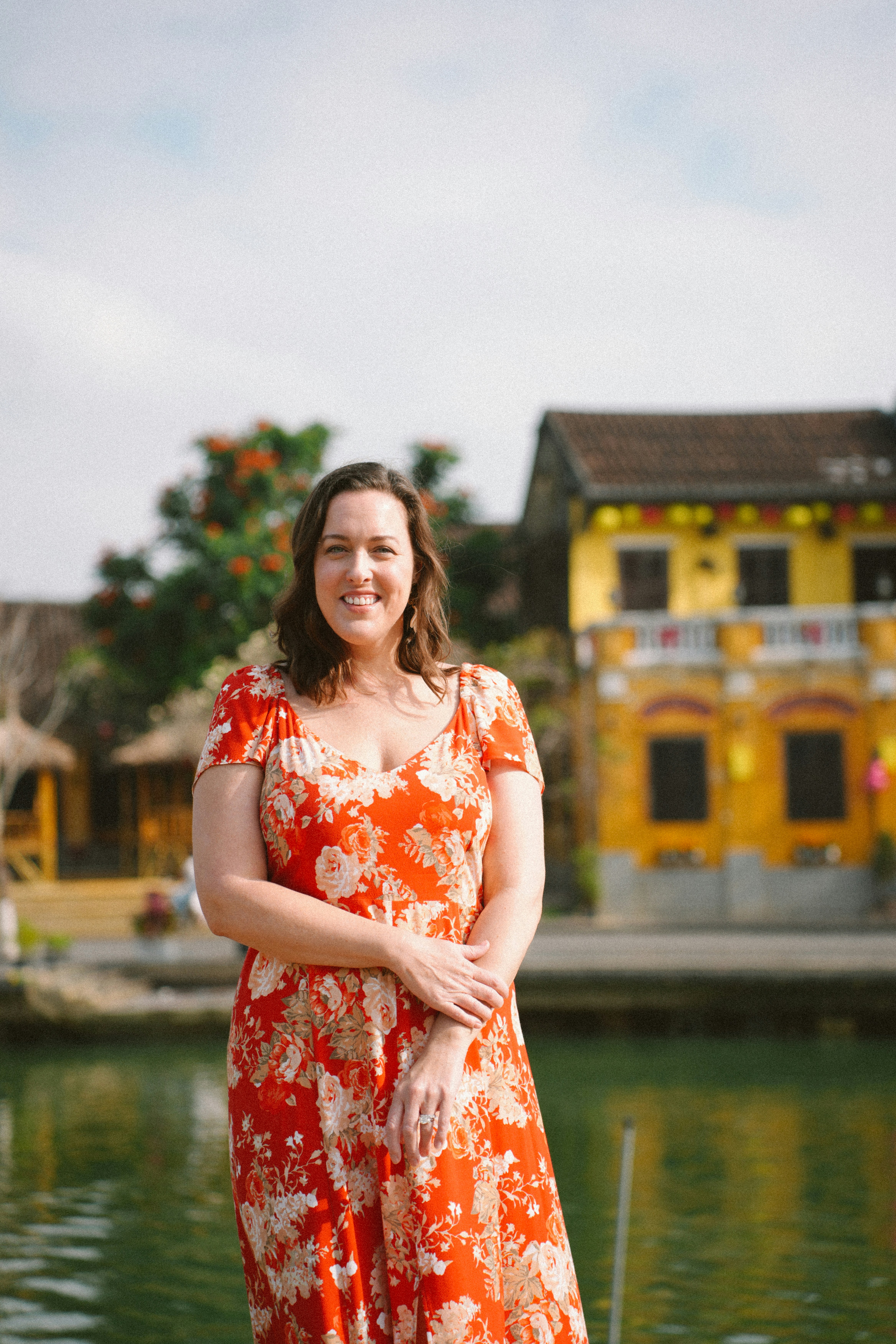 Sunlit Confidante in Orange Floral Dress by a Lakeside Village