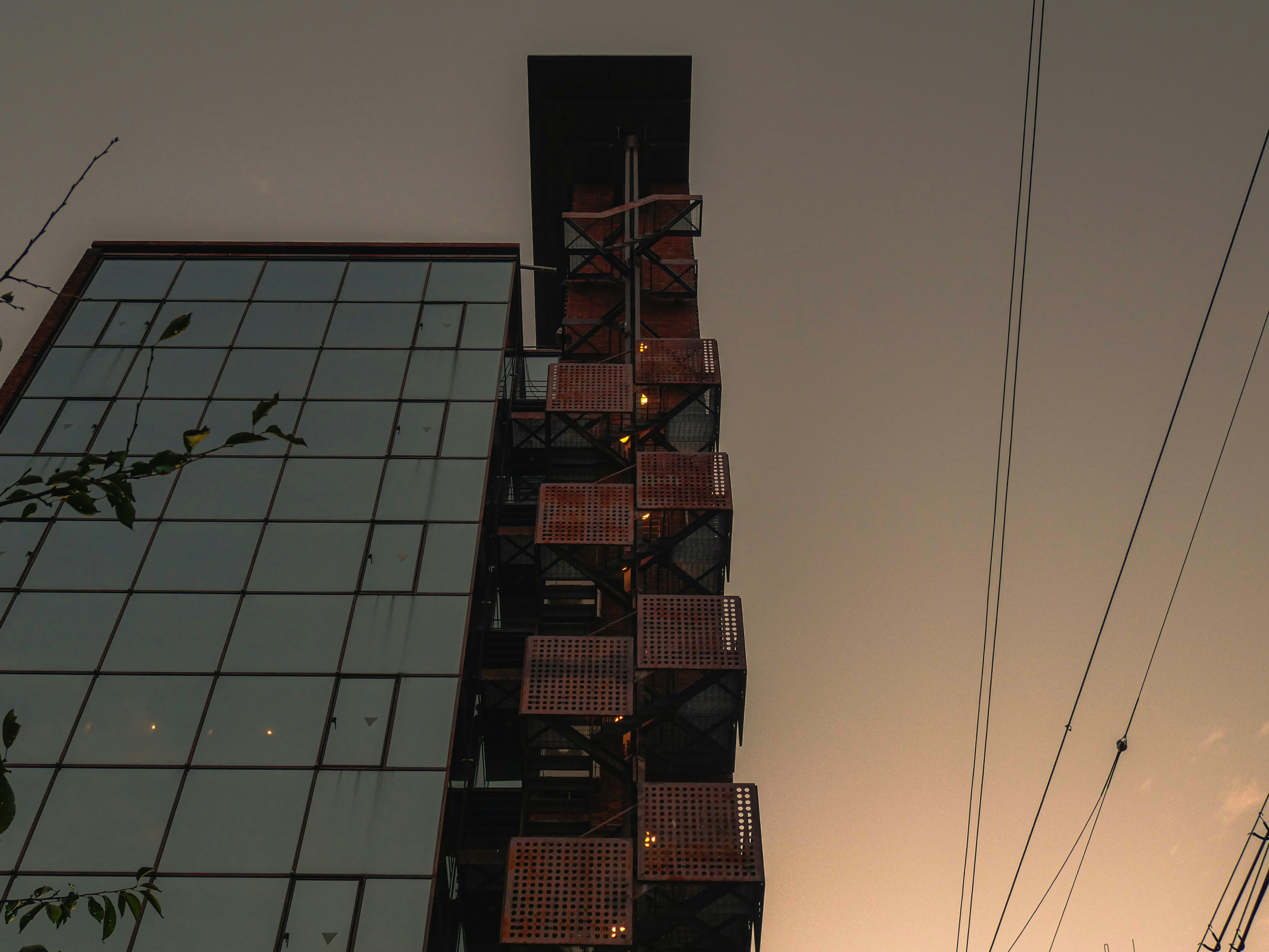 Vertical Staircase Tower Against Glass Facade at Dusk