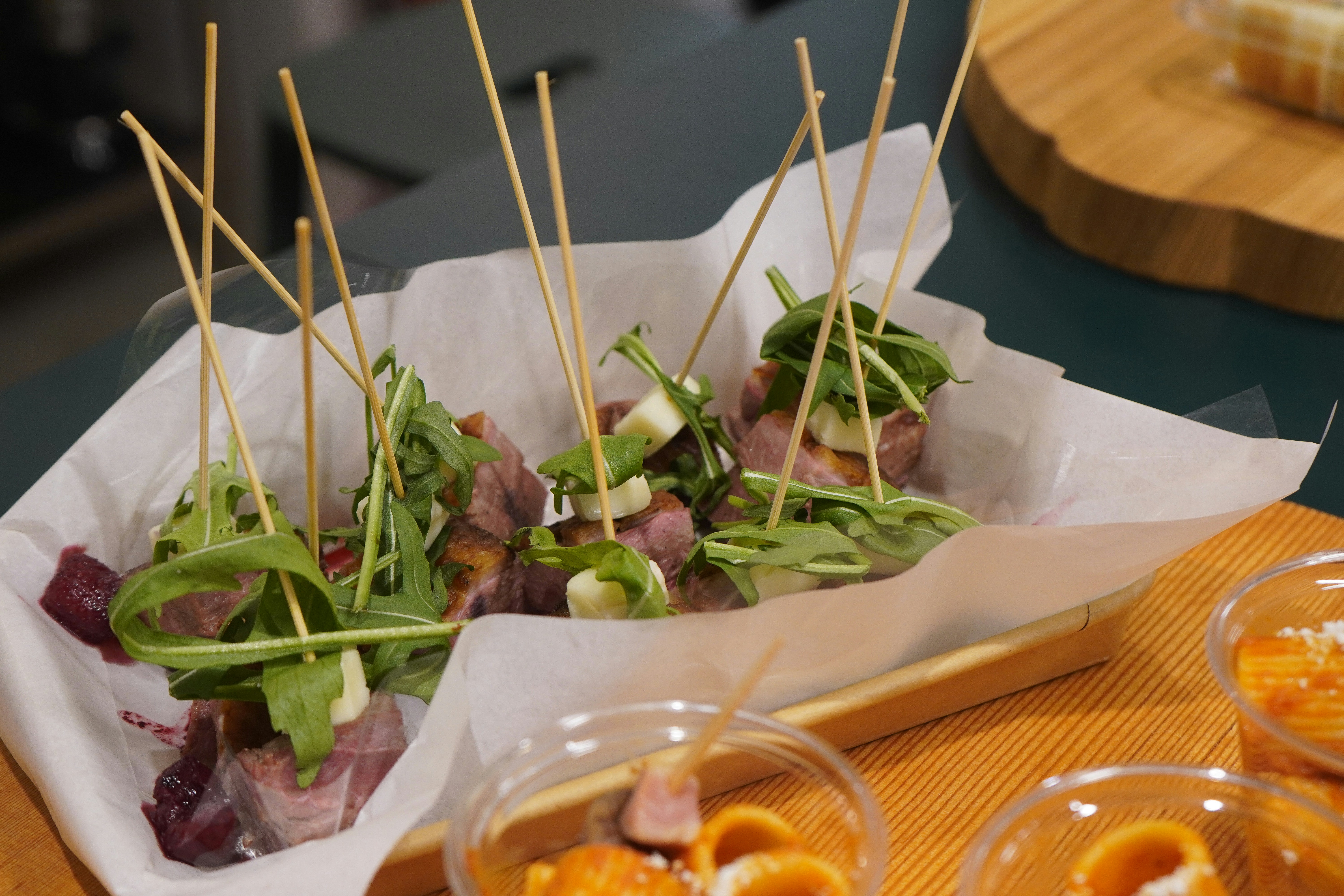 Skewered bites crowned with greens on parchment in a tasting spread