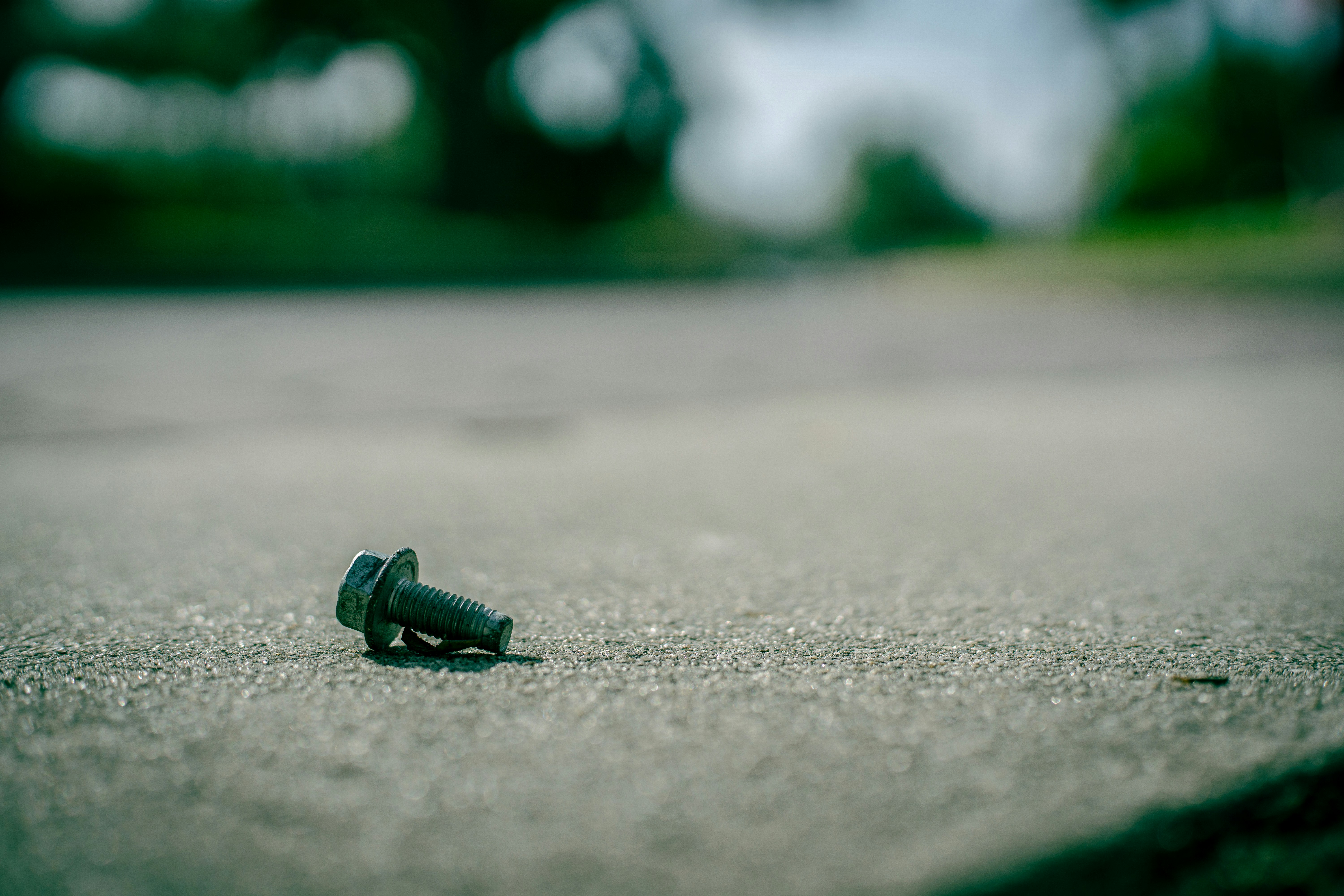 Grounded Bolt: A Lonely Fastener on a Quiet Asphalt Canvas