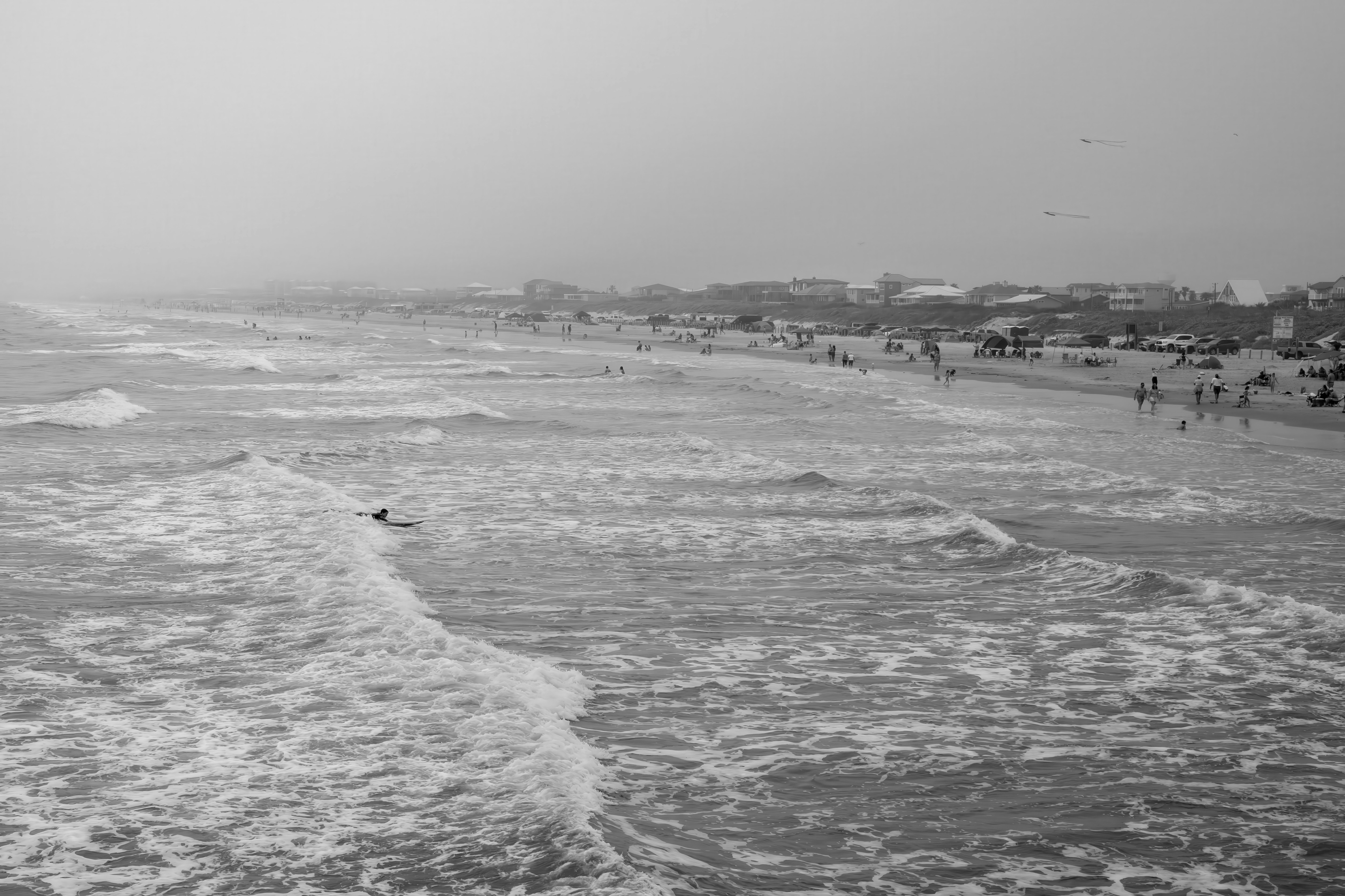 Coastal Grayscale: Quiet Surf and Distant Beachgoers
