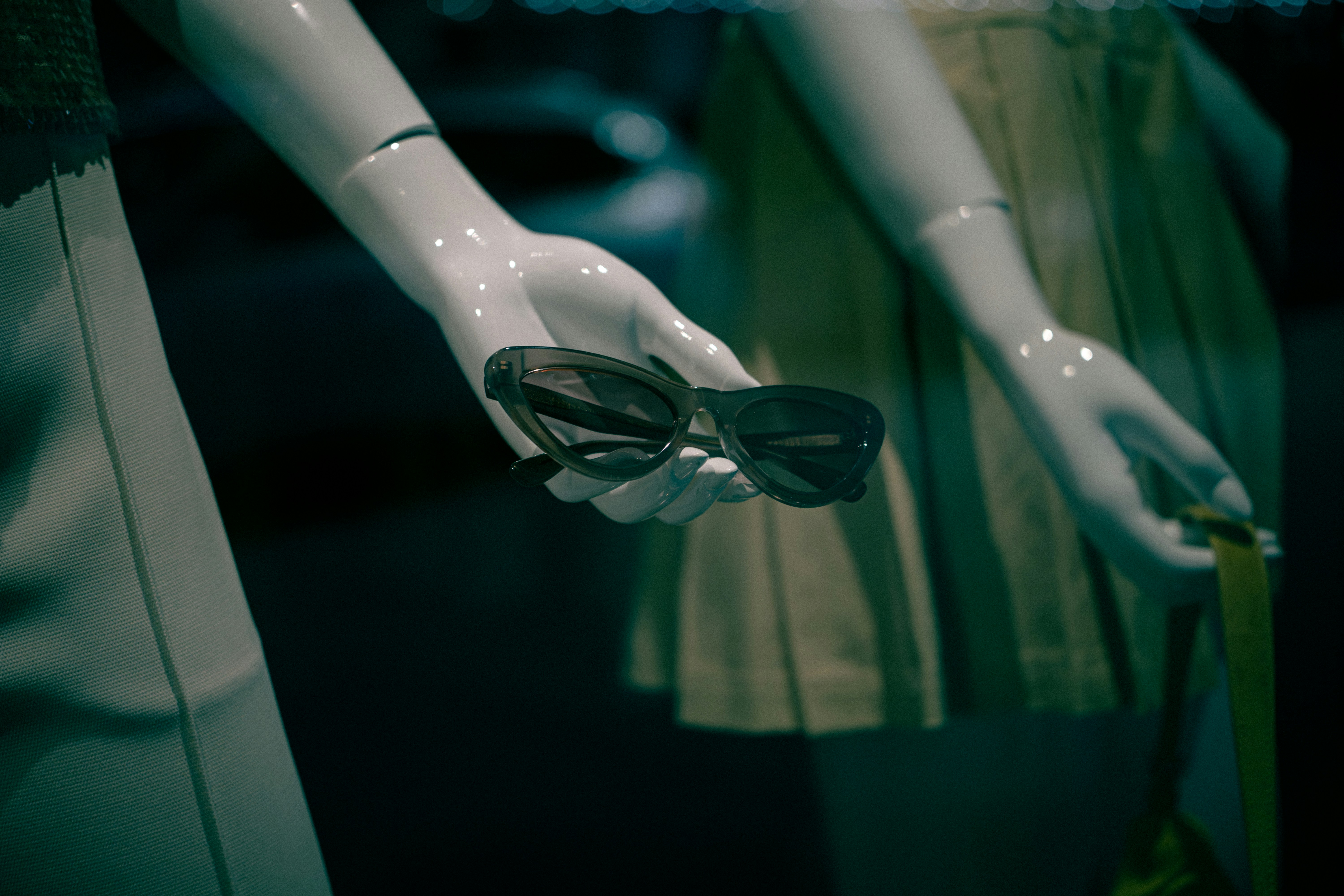 Shadowed Glass: Sunglasses Grasped Between Silent Mannequin Hands