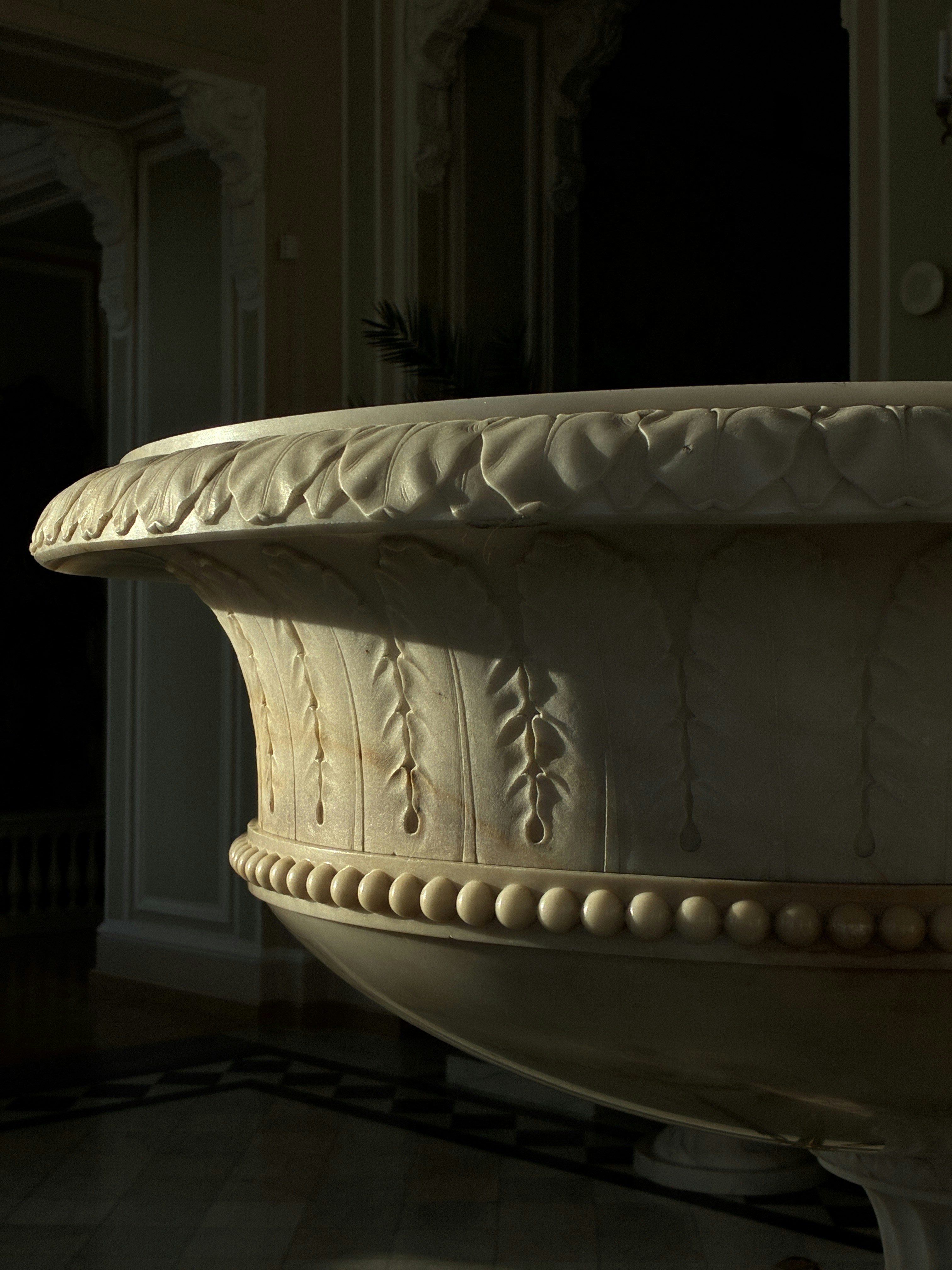 Ornate marble urn with decorative carvings and beading.
