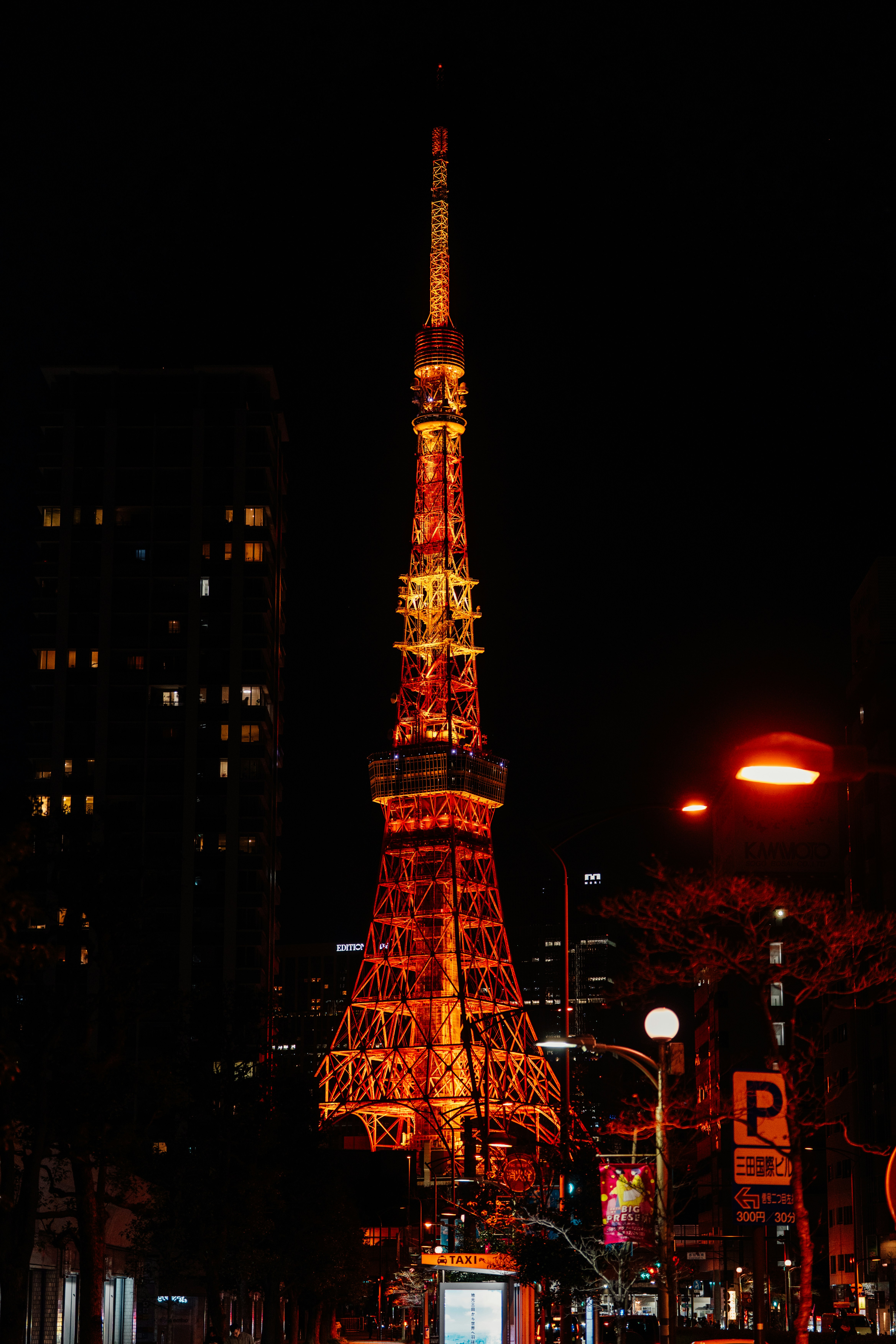 Tokyo Tower Illuminated: Nighttime beacon over a neon-lit street