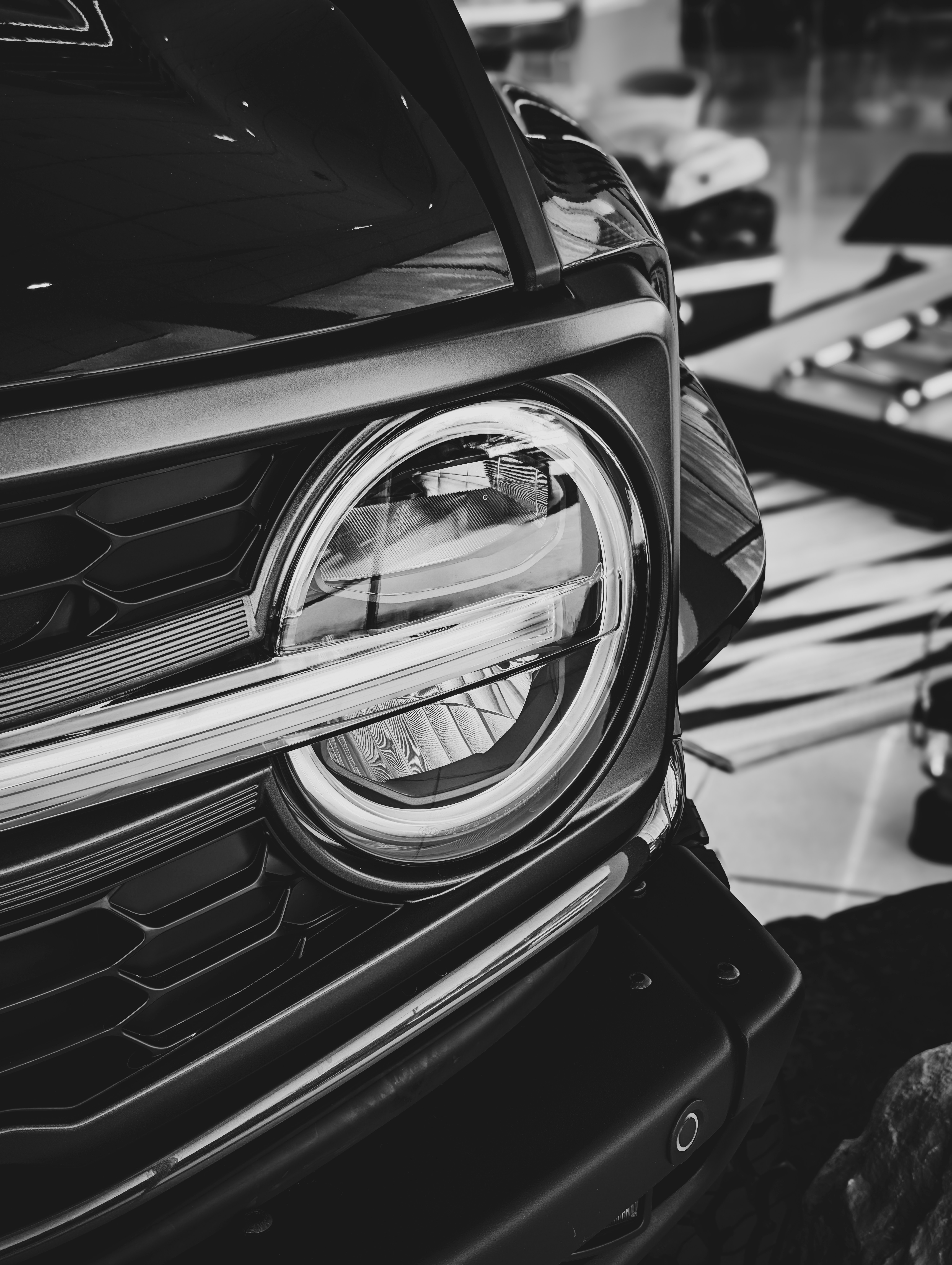 Close-Up of a Rugged Car Front: Headlight Detail in Monochrome