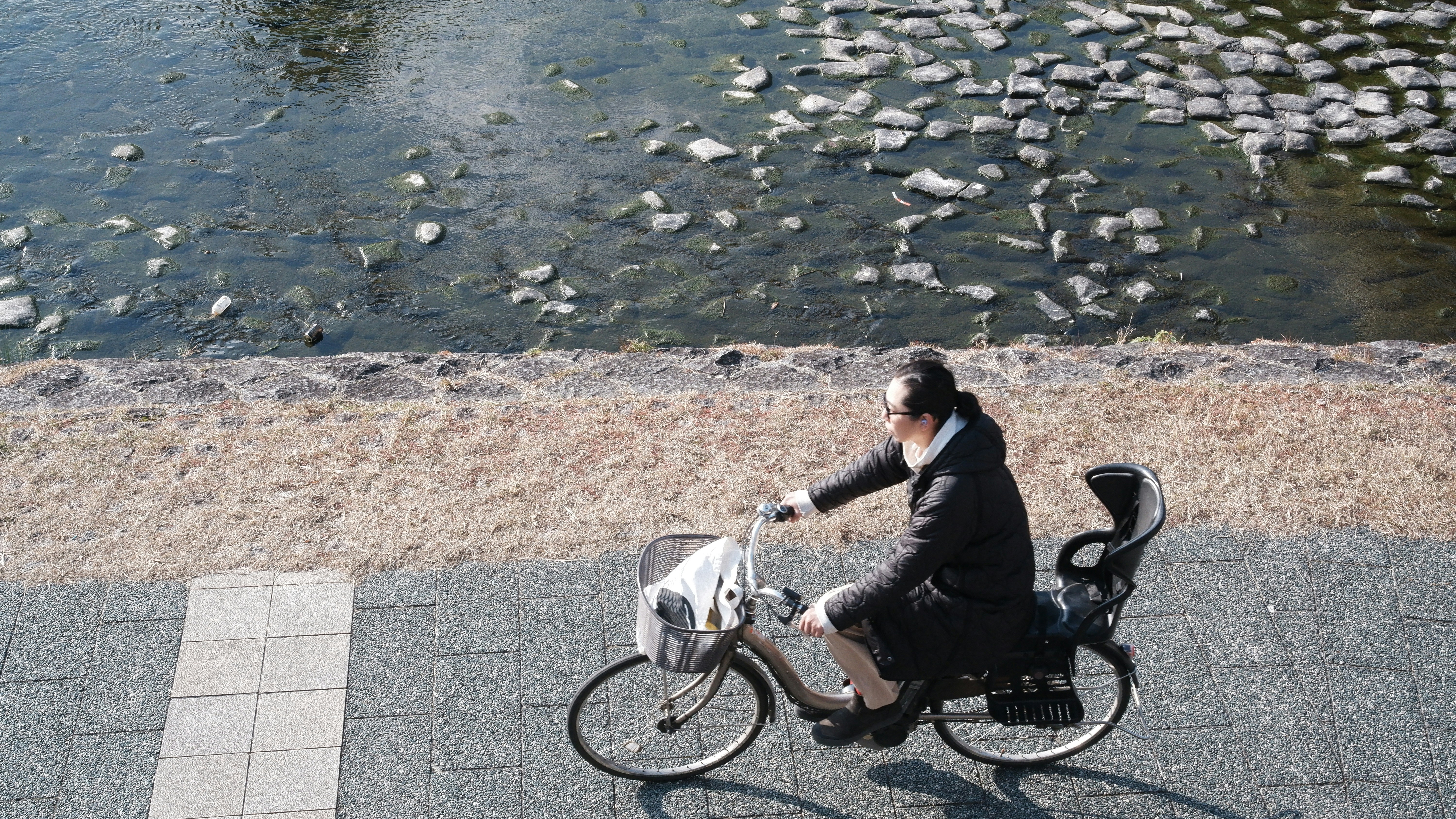 Pedal along the riverfront: a solitary commuter in the urban light