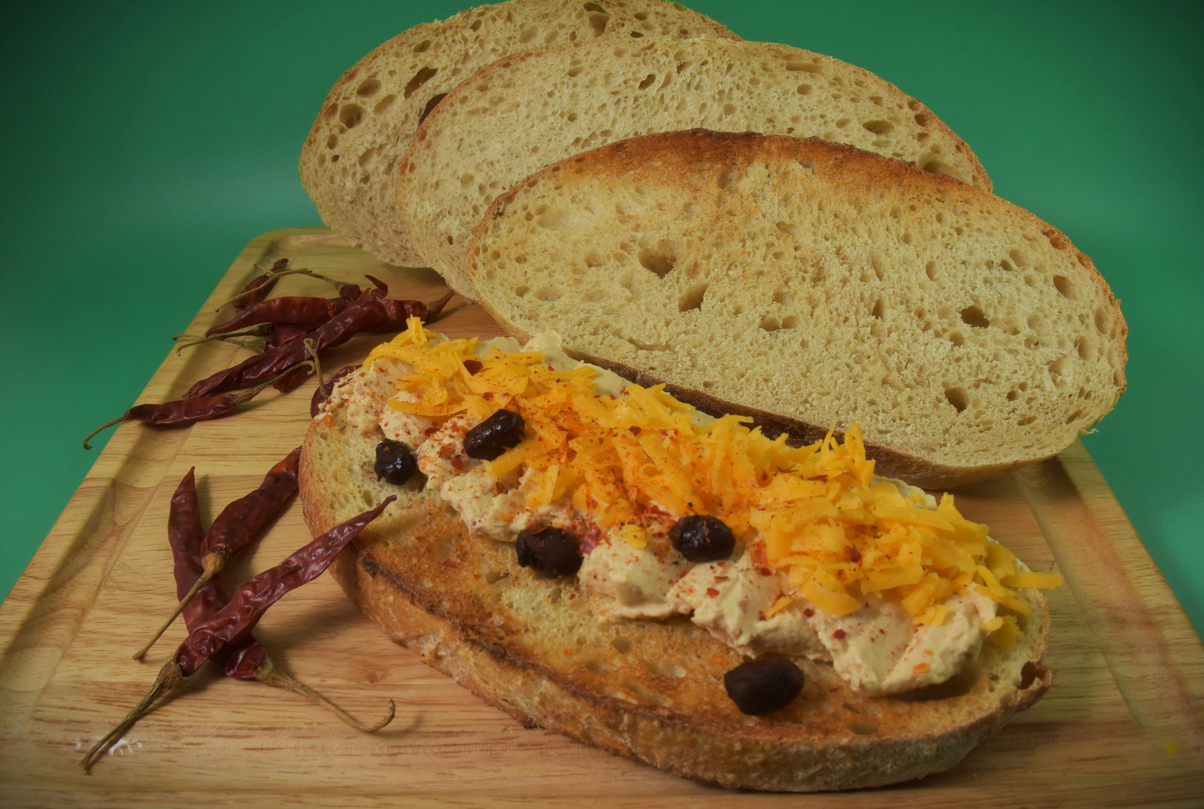 Open-Faced Cheesy Olive Baguette on a Rustic Board