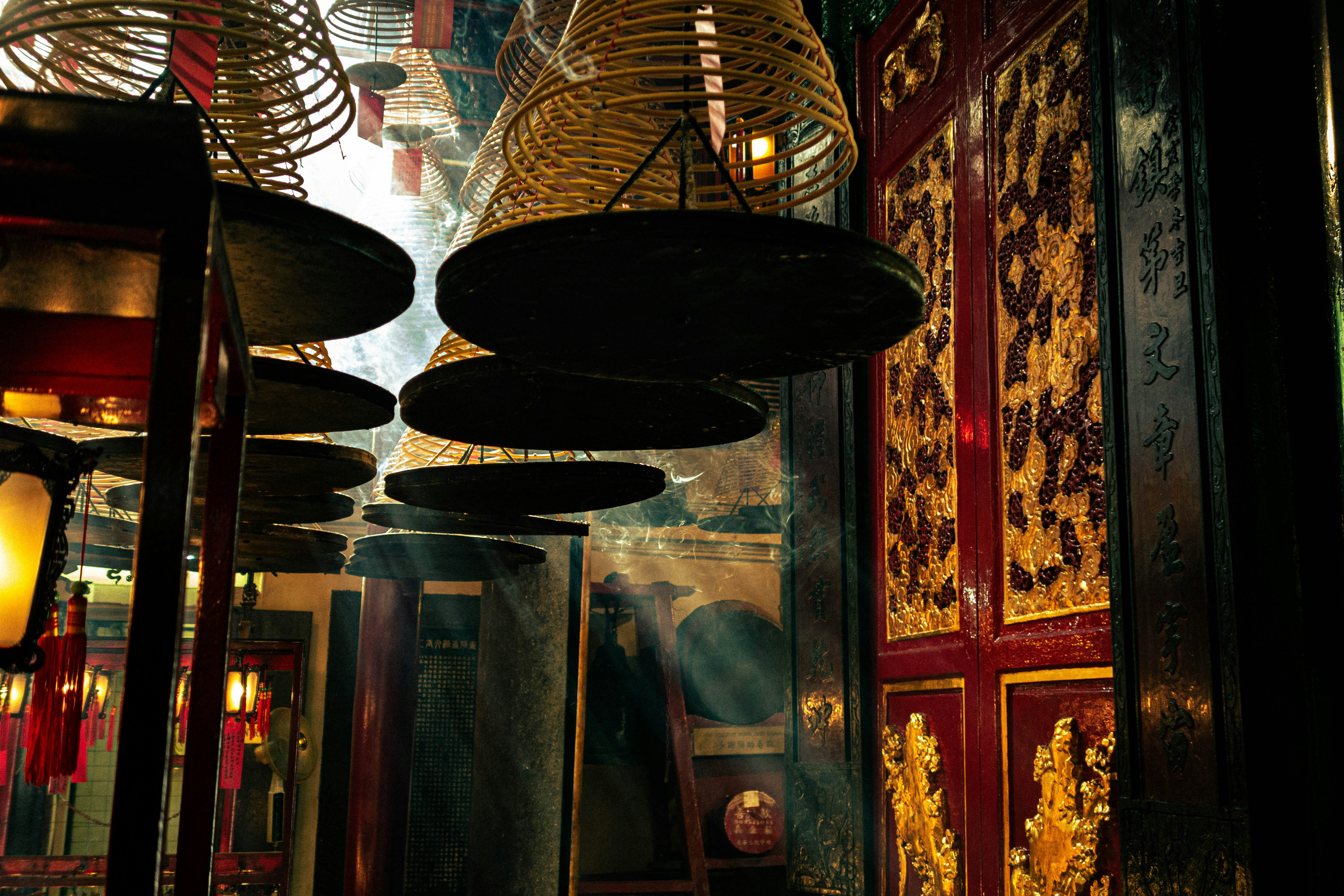 Hanging Vessels and Ornate Panels in a Dim Temple Corridor