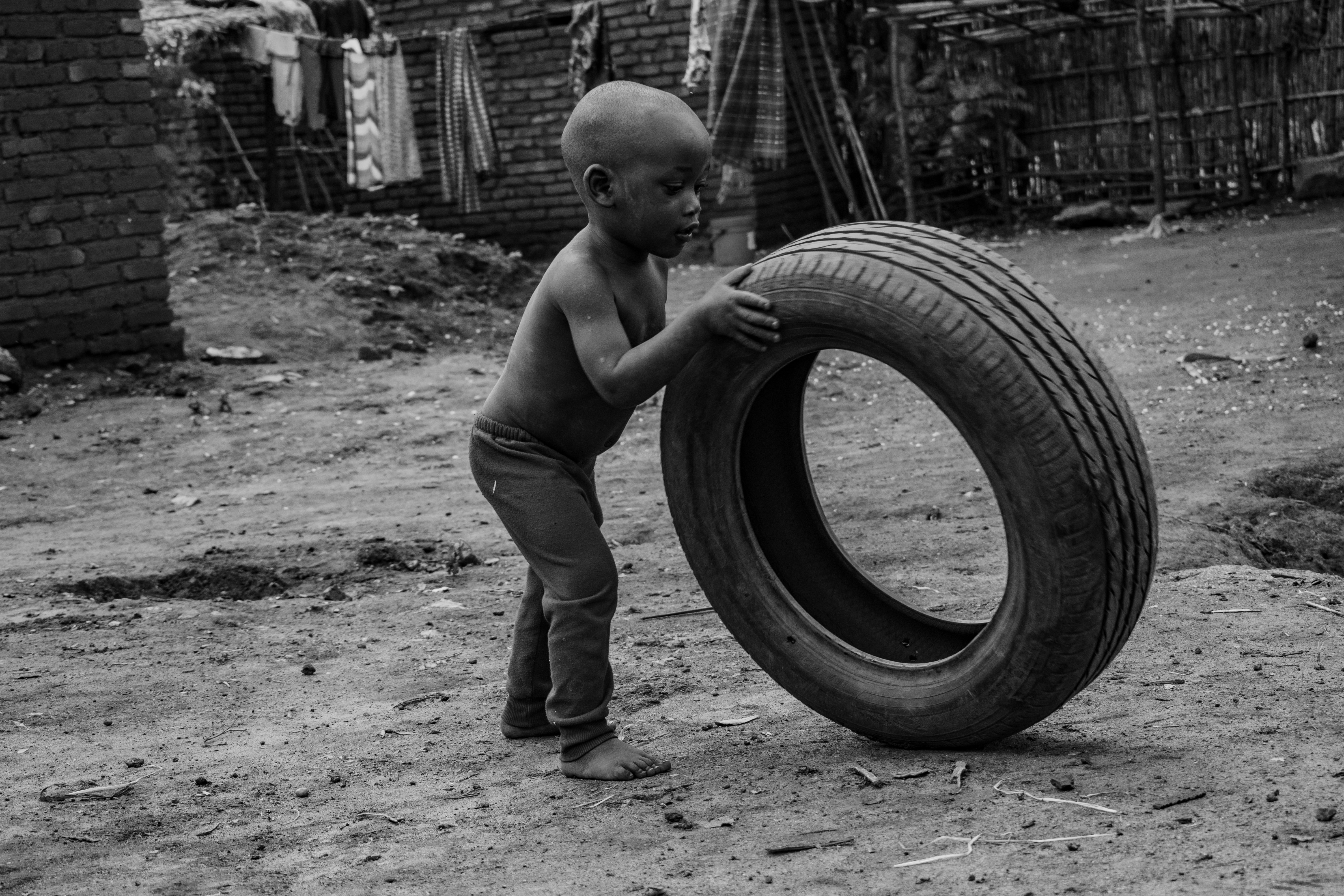 Child with Tire: Quiet Moment of Play in a Dusty Yard