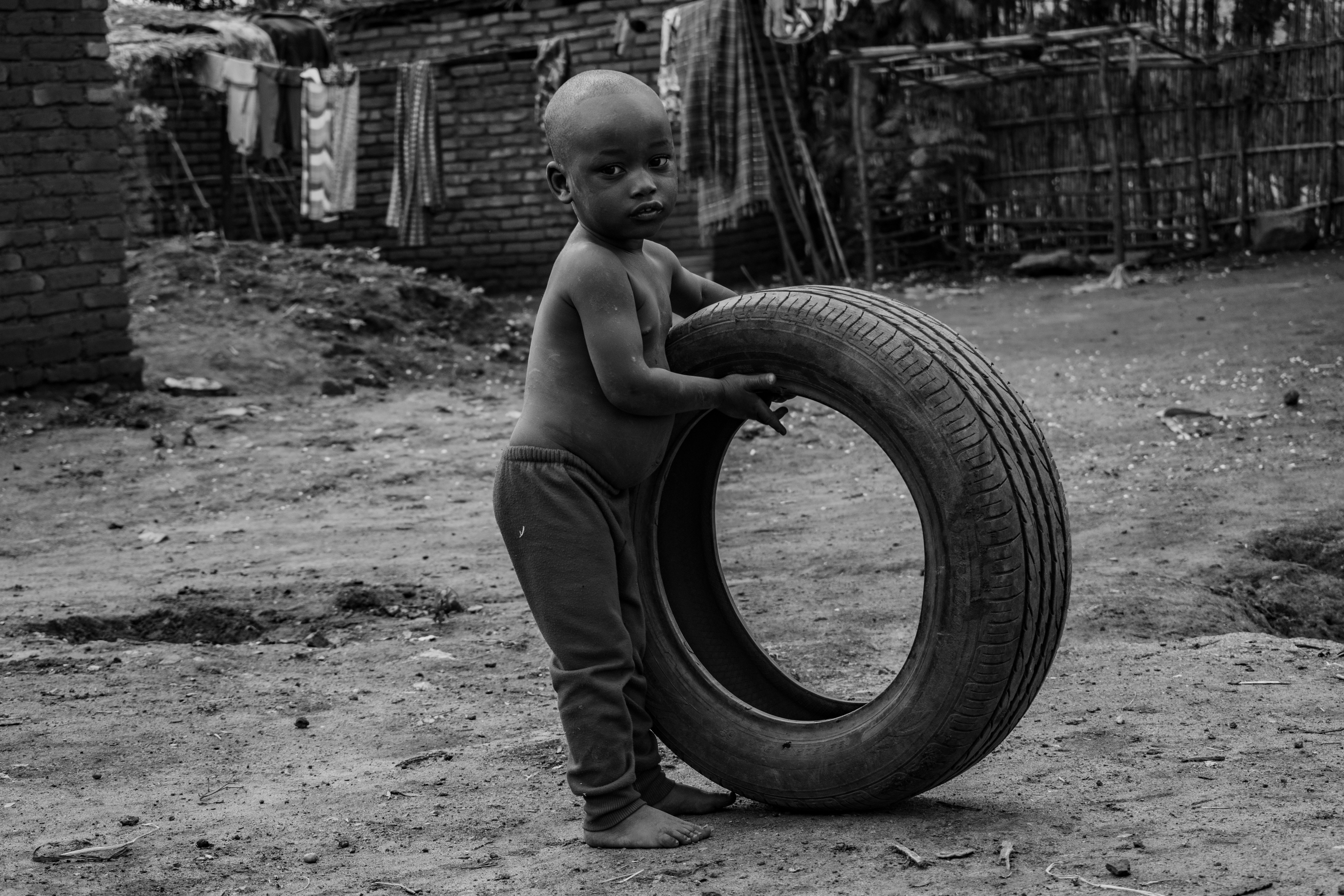 Child with Tire: A Quiet Moment on a Dusty Yard