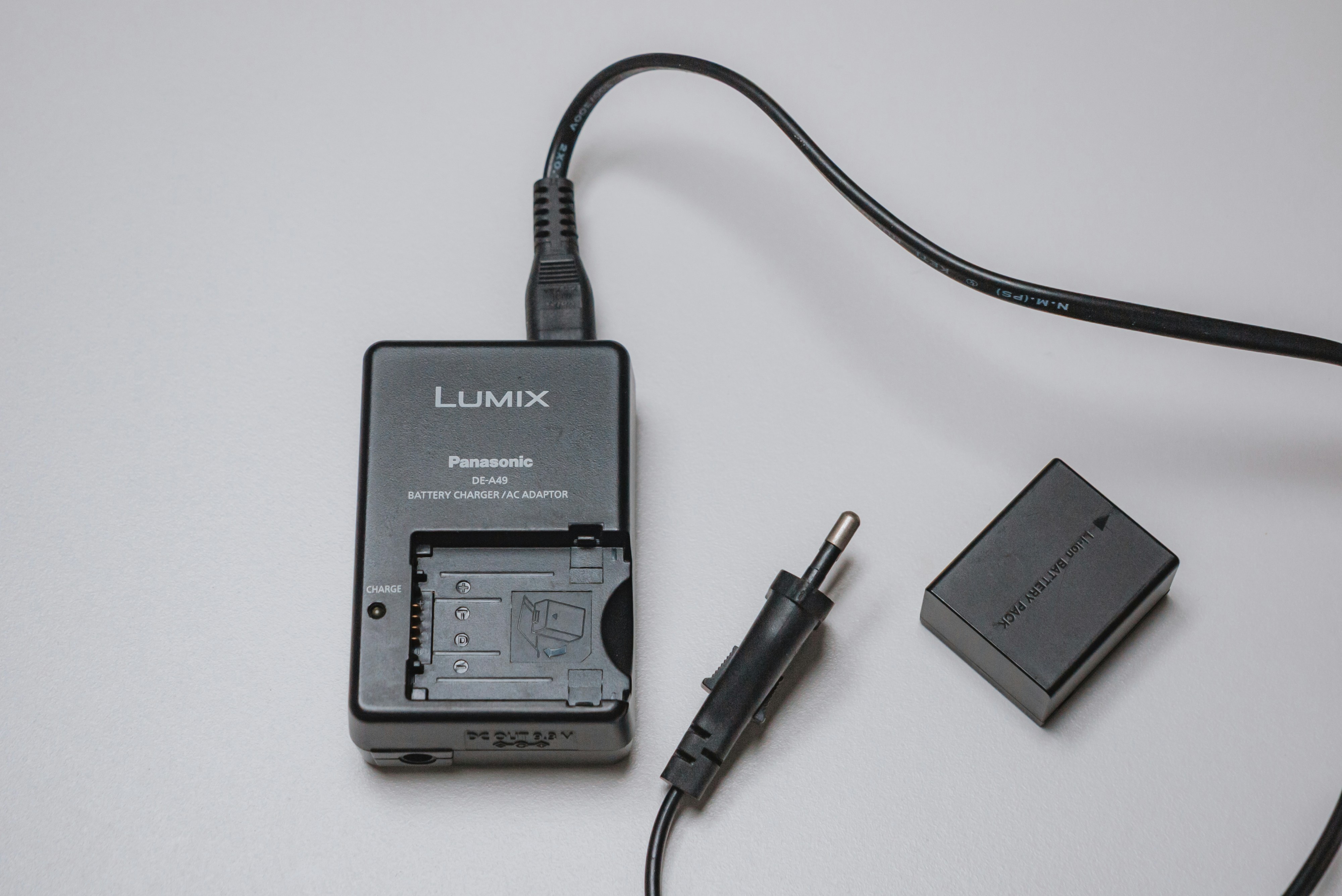 A lumix battery charger with a battery and plug.