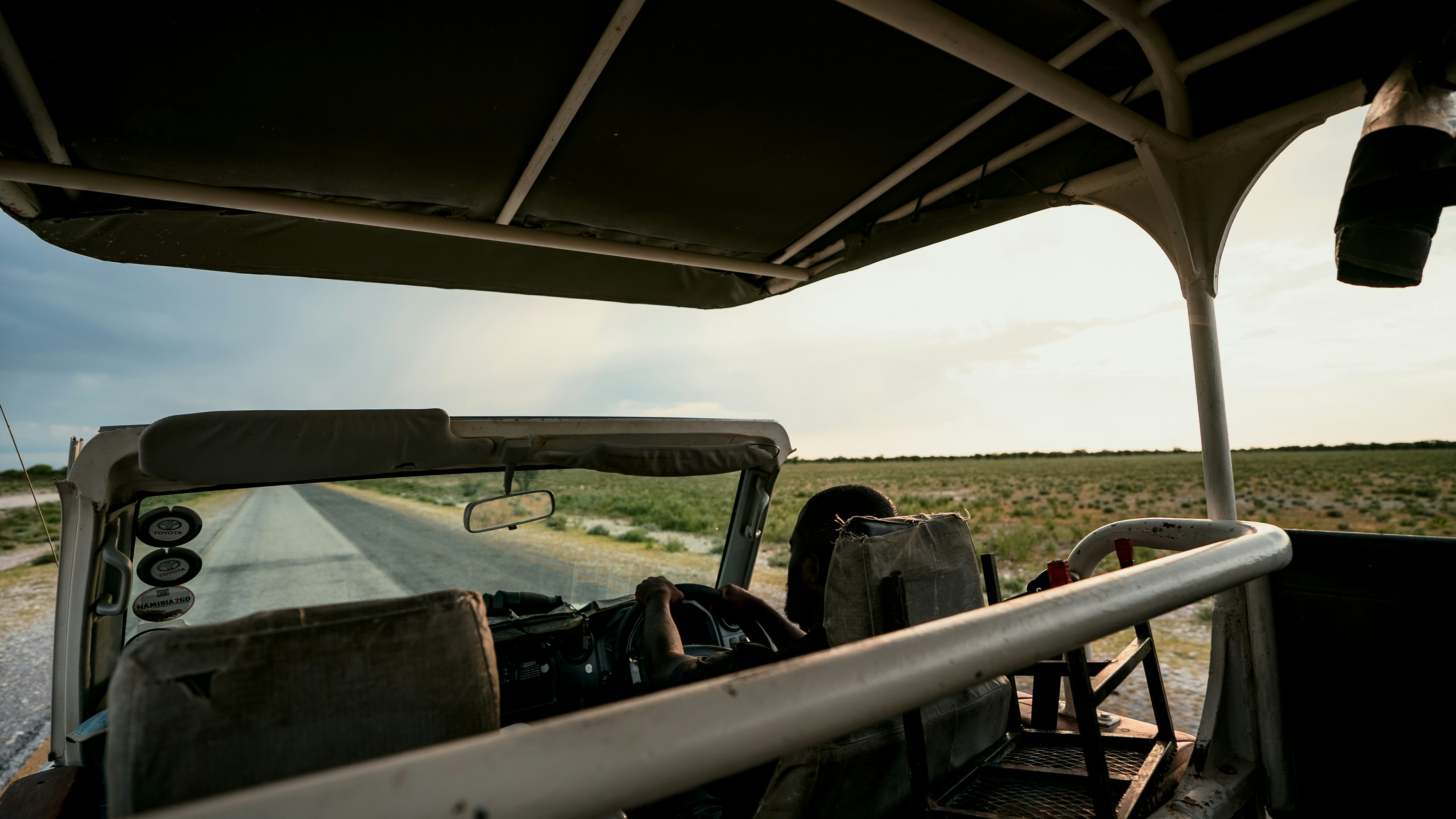 View from inside a safari vehicle on a dirt road.