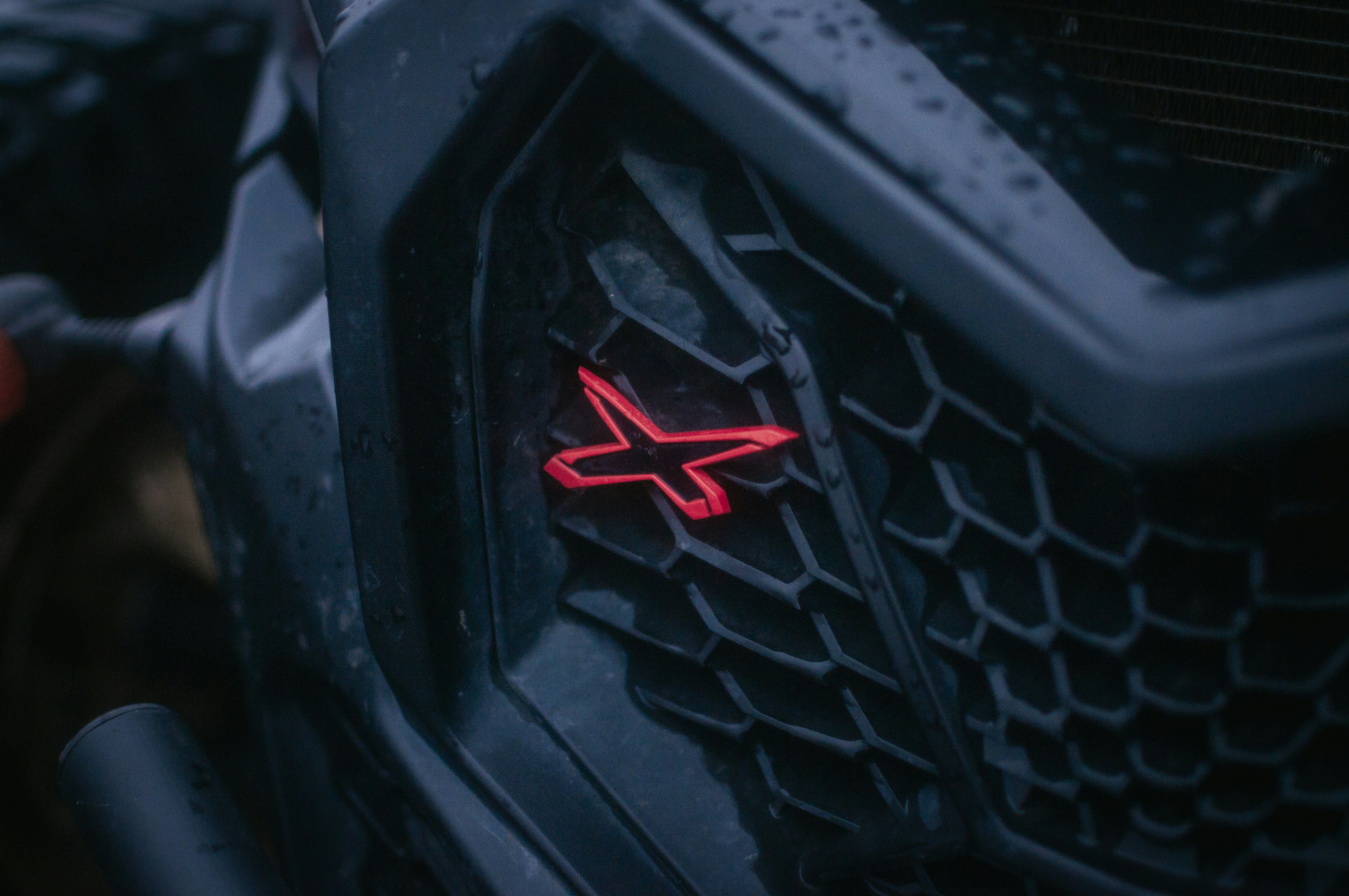 The Red X Emblem Grips the Grille in Rain-Kissed Focus