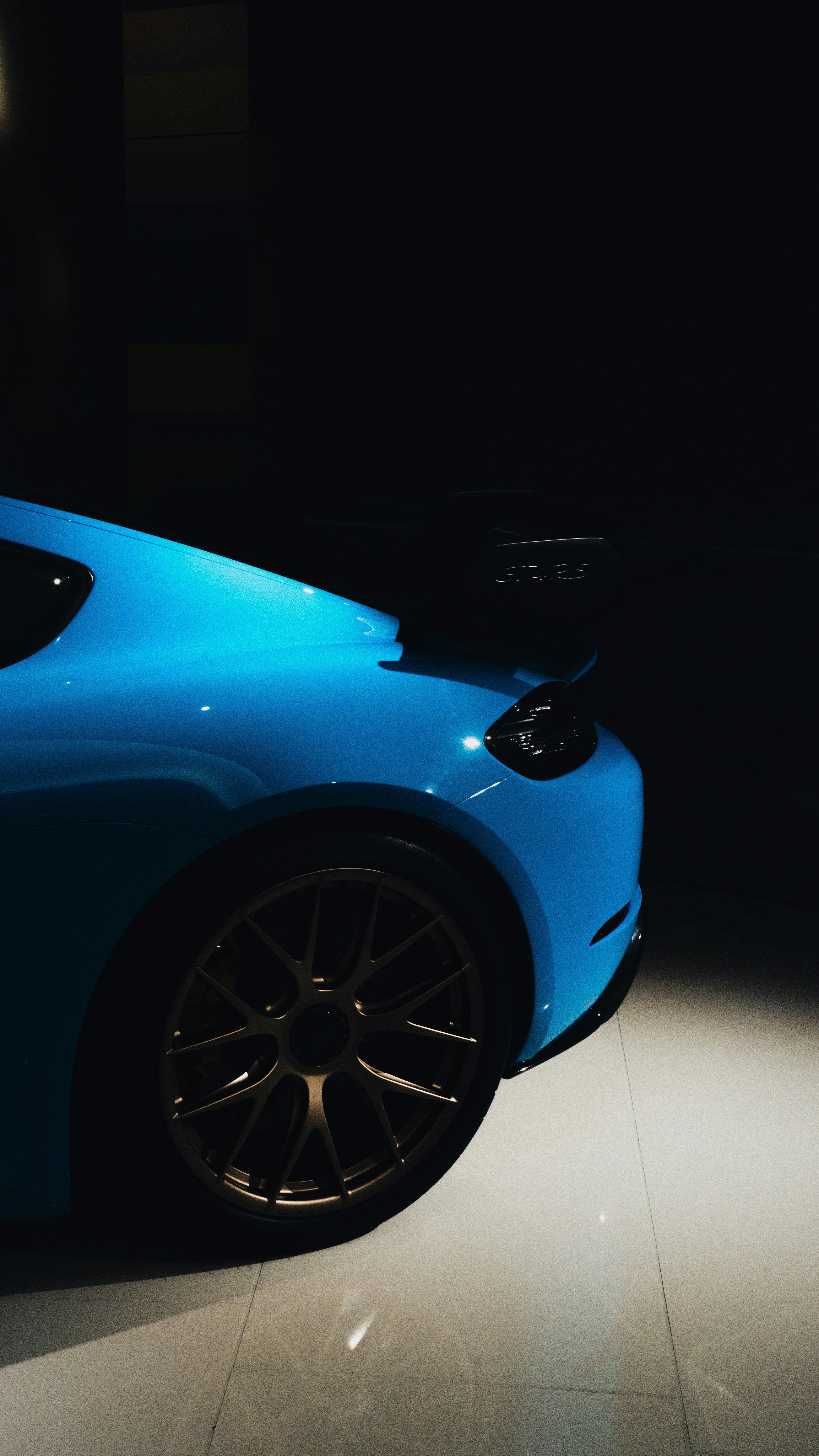 Midnight blue Porsche silhouette: partial rear-quarter under showroom glow