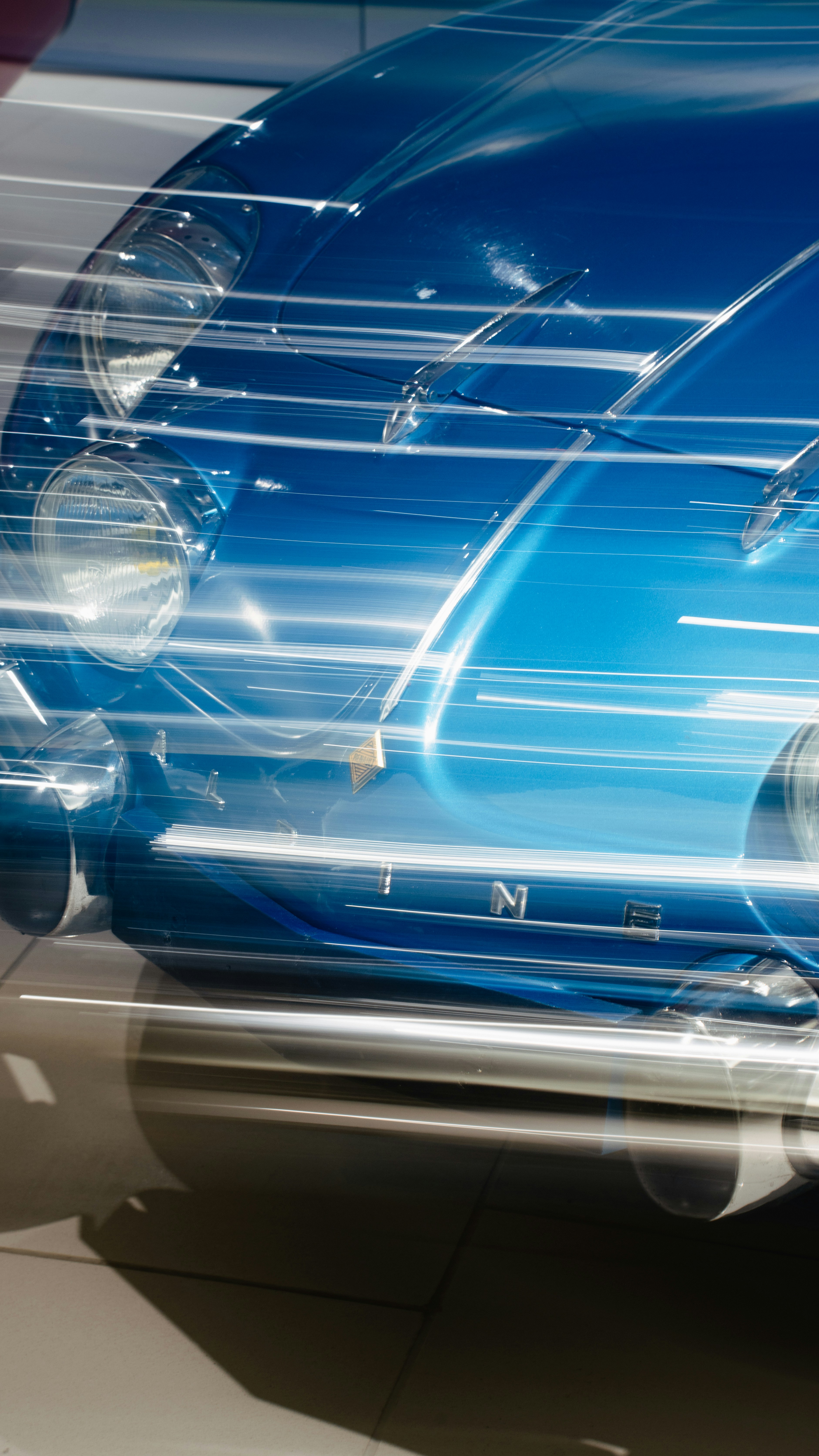 Blue Classic: The Front Edge of a Vintage Jaguar Gliding Through Motion Trails