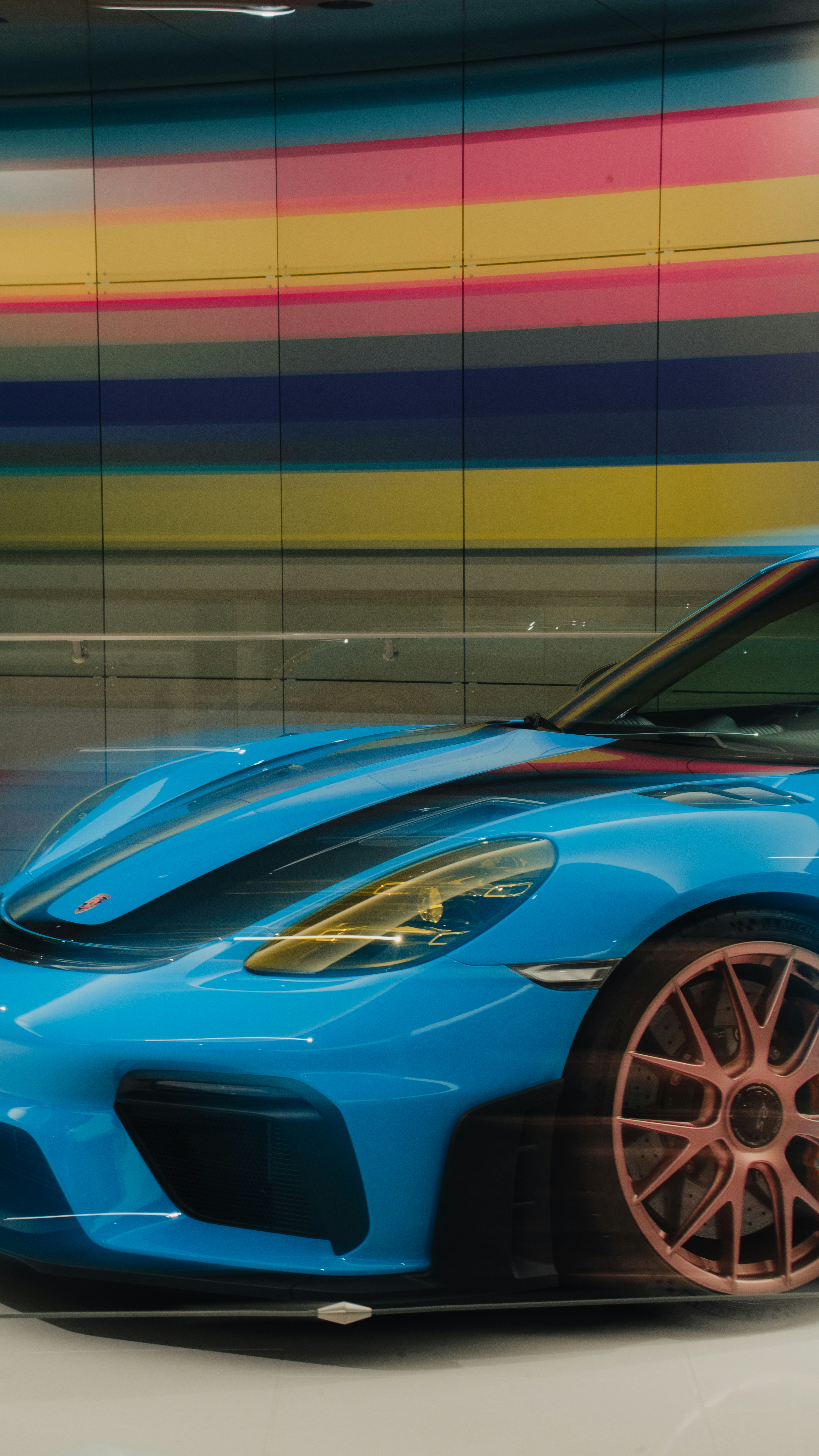 Blue hypercar in a rainbow-aligned showroom