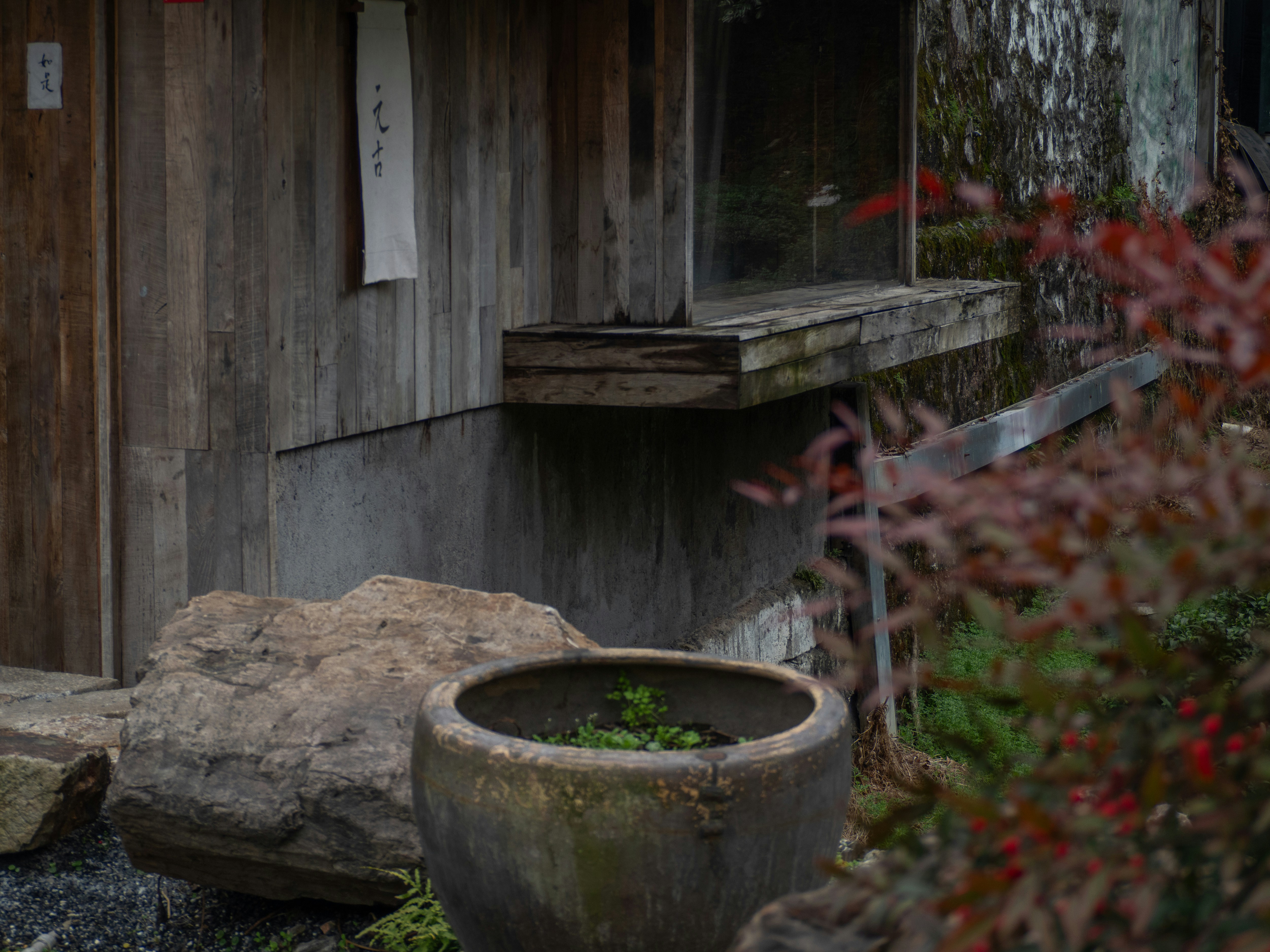 Old wooden building with a stone pot and plants
