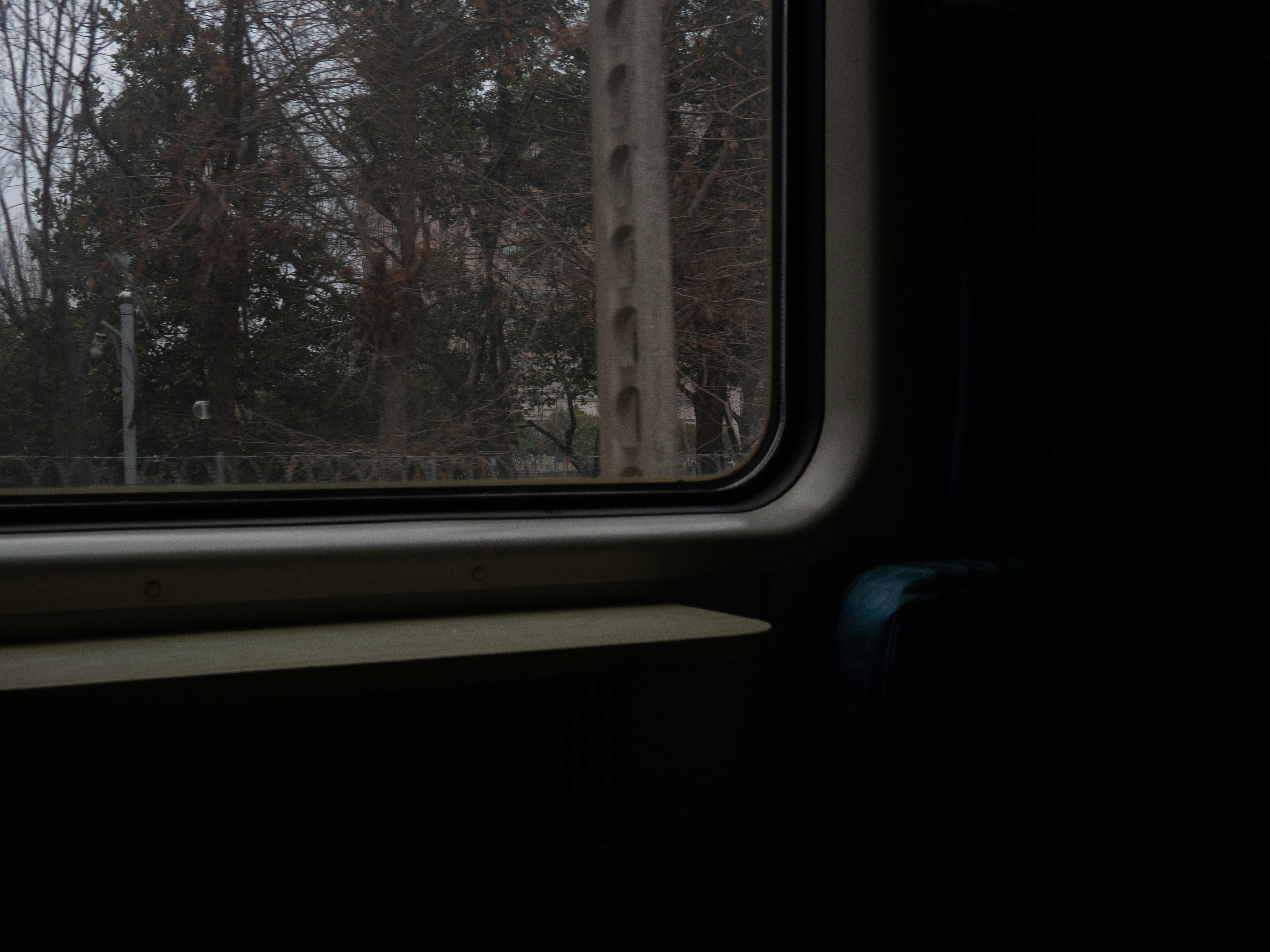 Dim Train Window — Quiet Landscape Beyond the Car Window