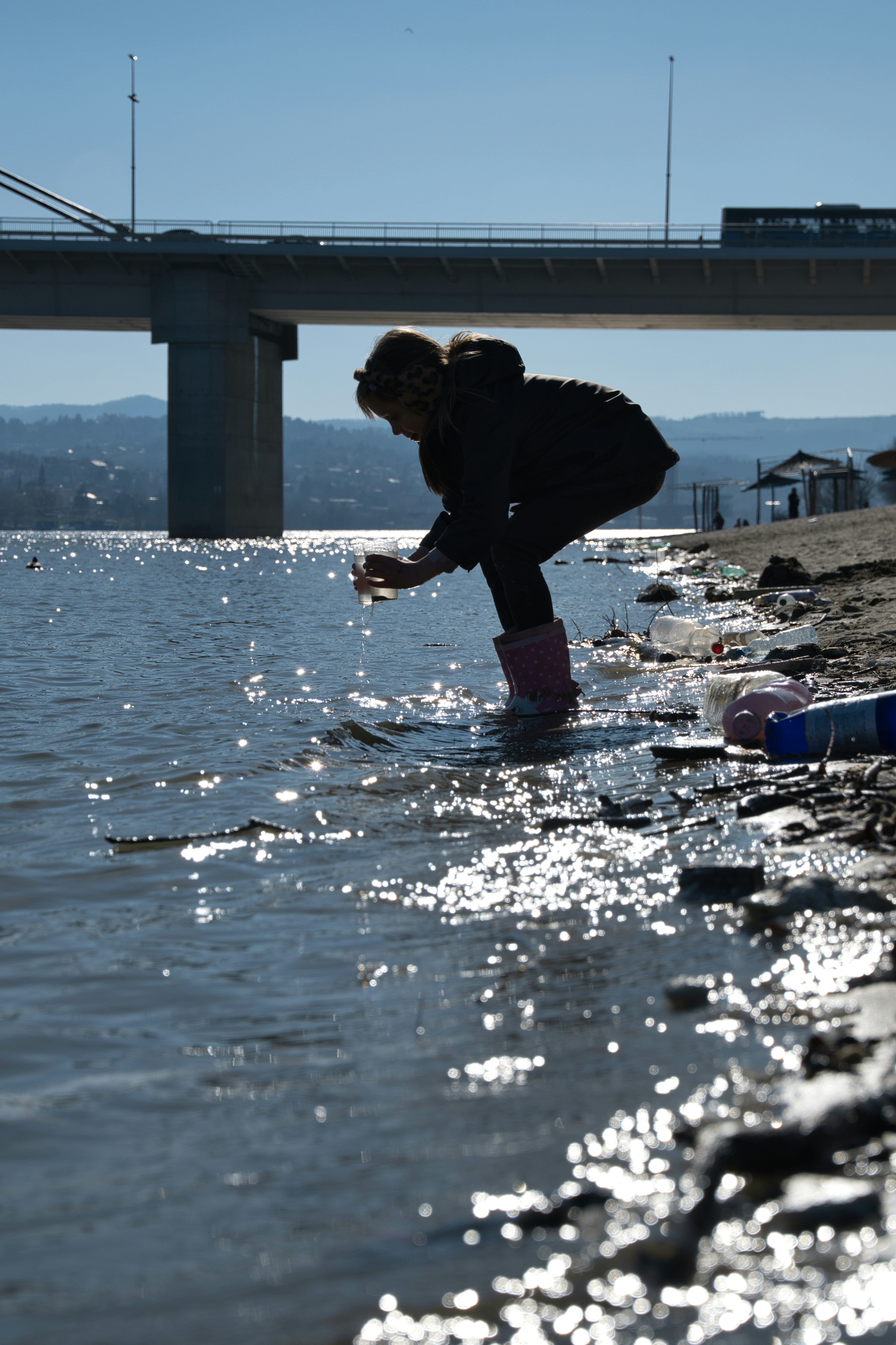 Sketching Ripples: A child’s bent silhouette exploring the shoreline