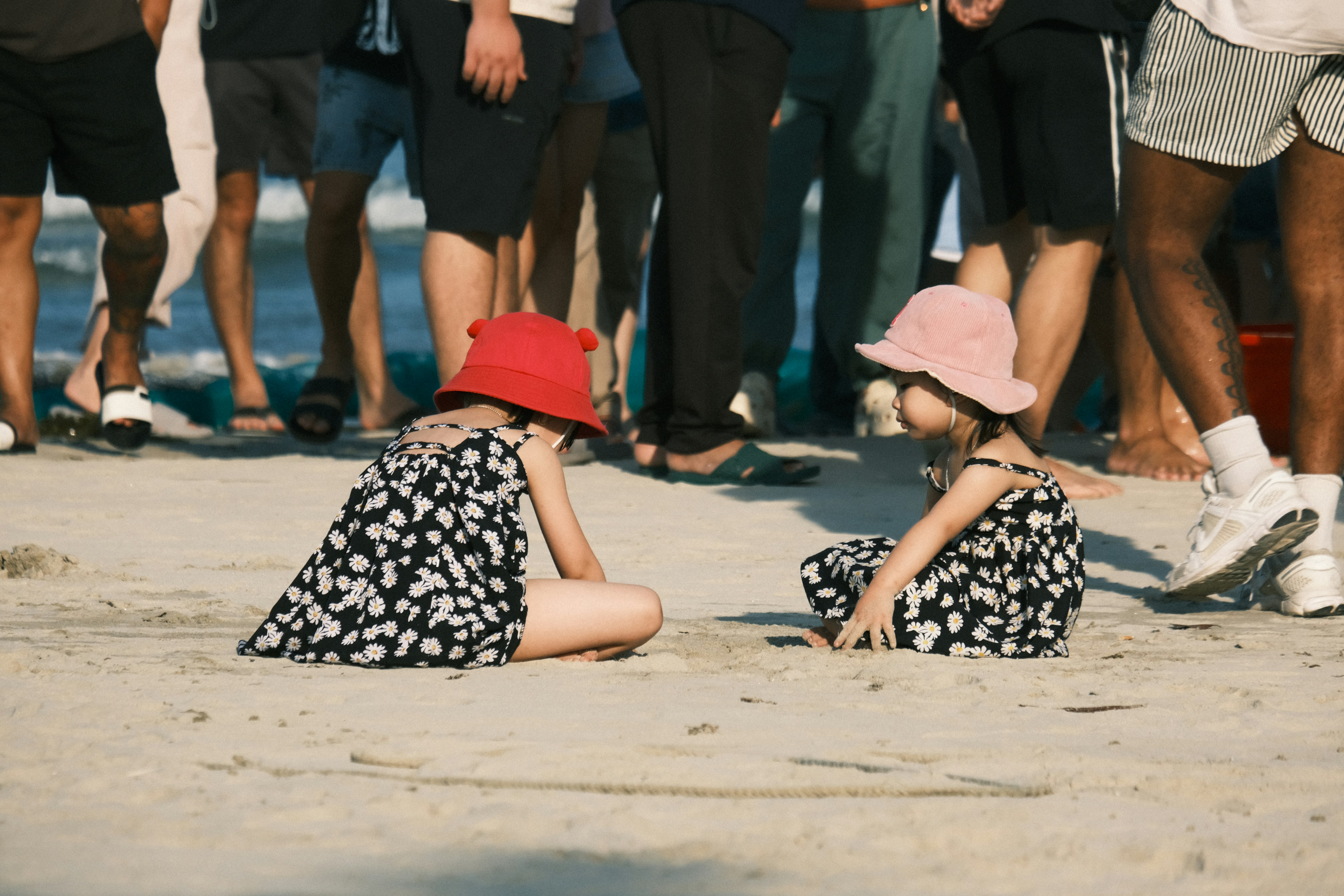 Sandbound Quiet: Two Dressed for a Moment Amid the Crowd