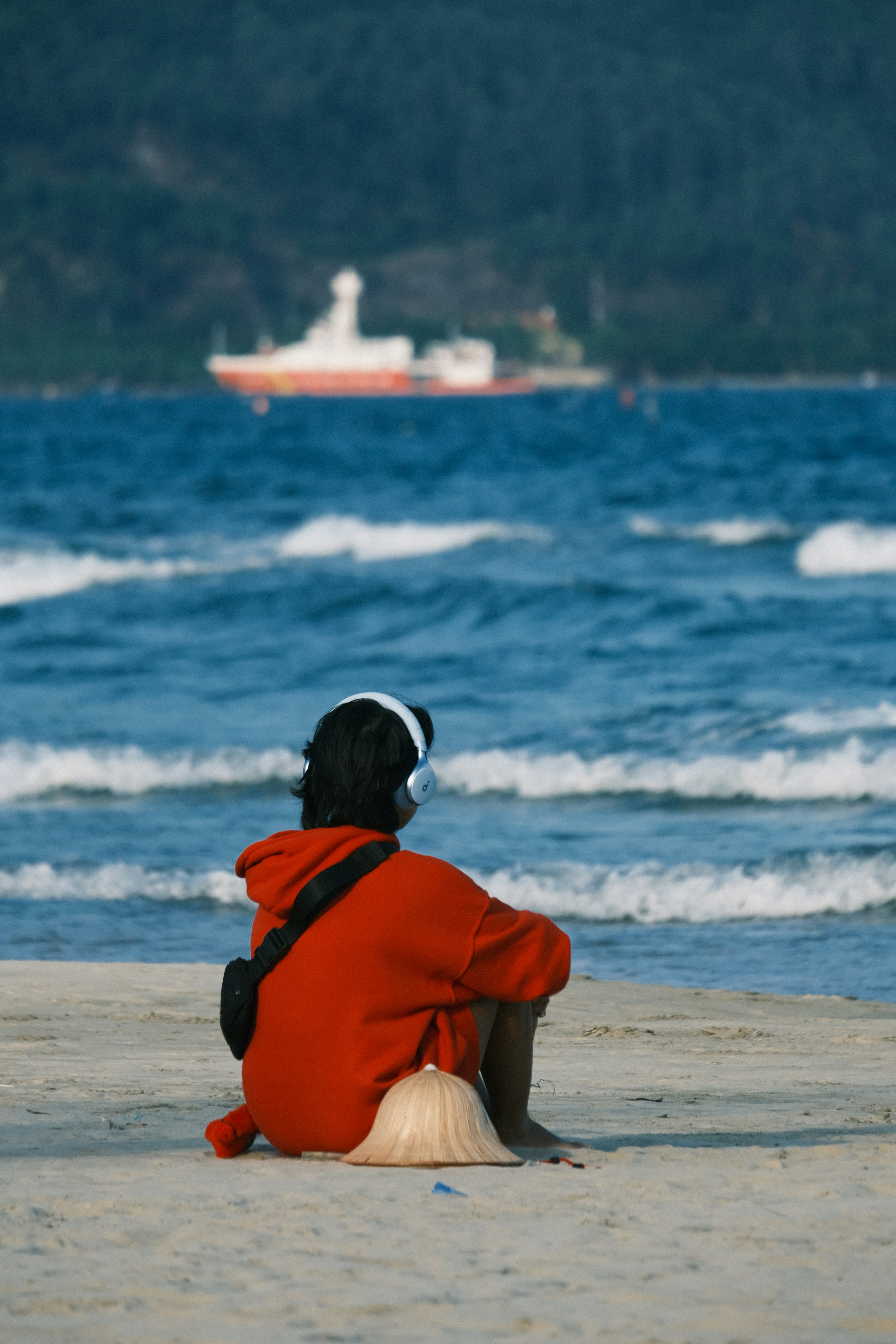 Coastal Quiet: A Red Hoodie and White Headphones by the Sea